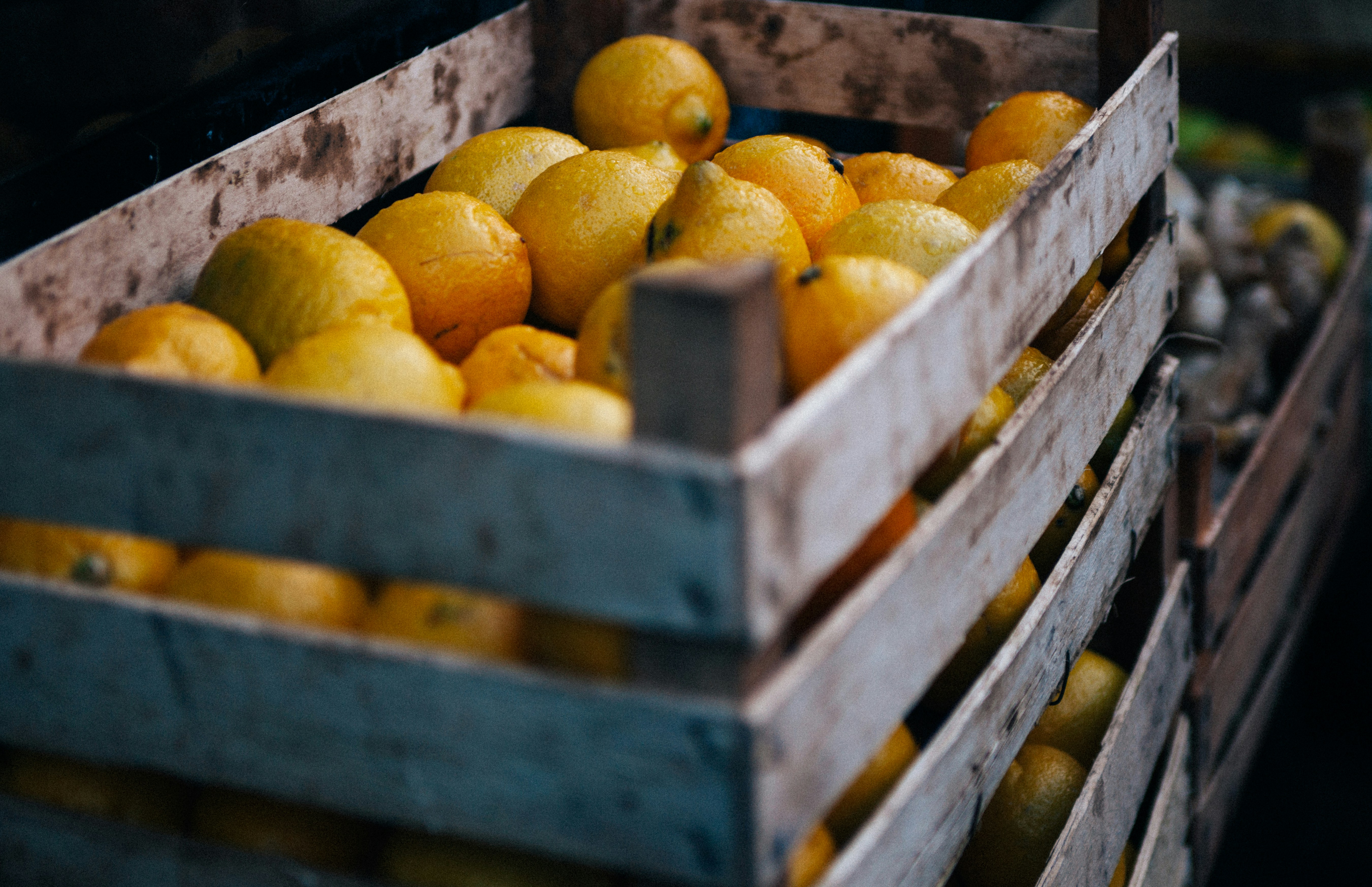Wooden crates filled with ripe lemons stacked in a dimly lit market.