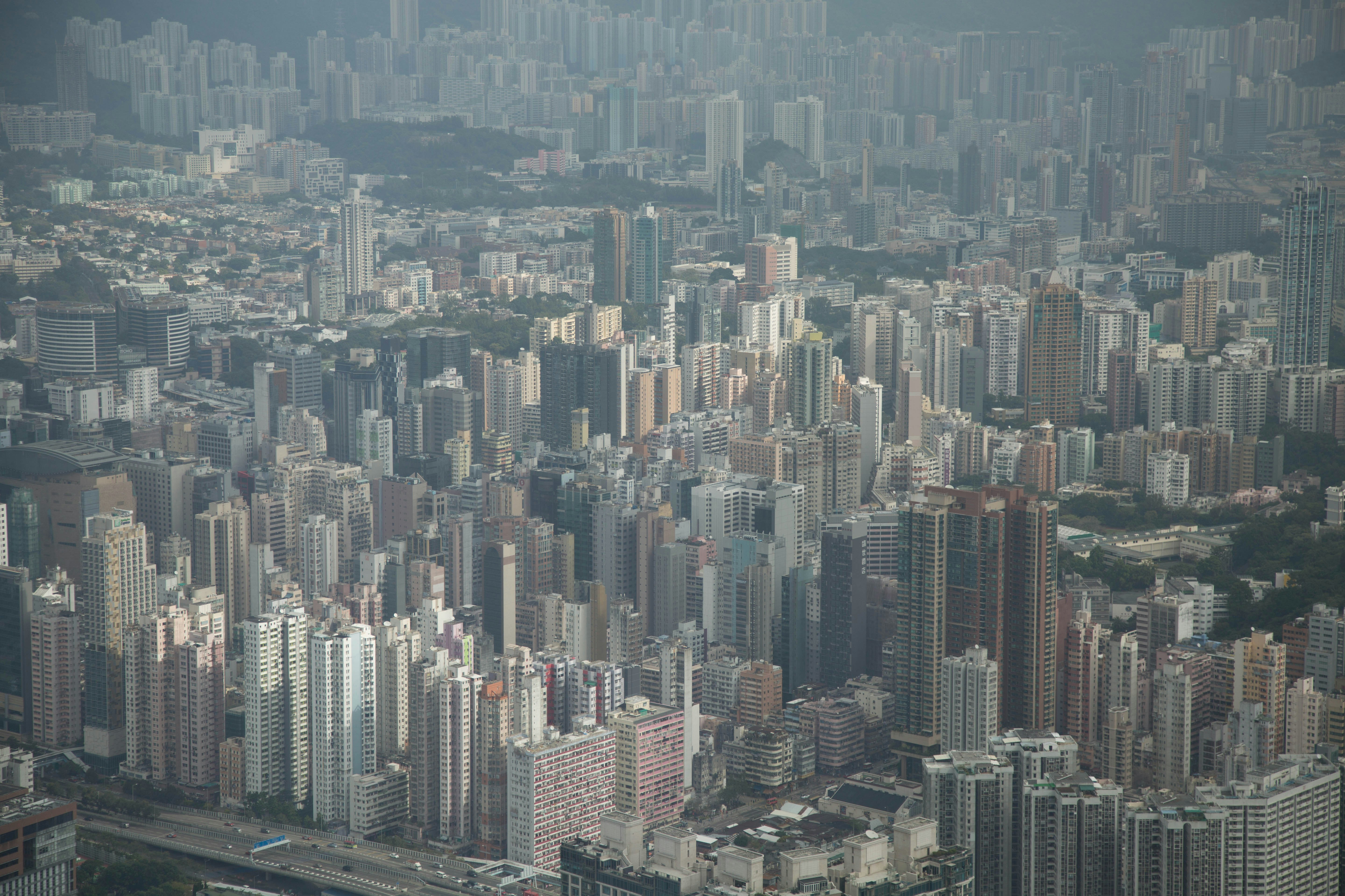 Aerial view of a densely populated cityscape, showcasing a vibrant array of high-rise buildings and urban structures. The scene highlights the complexity of modern architecture.