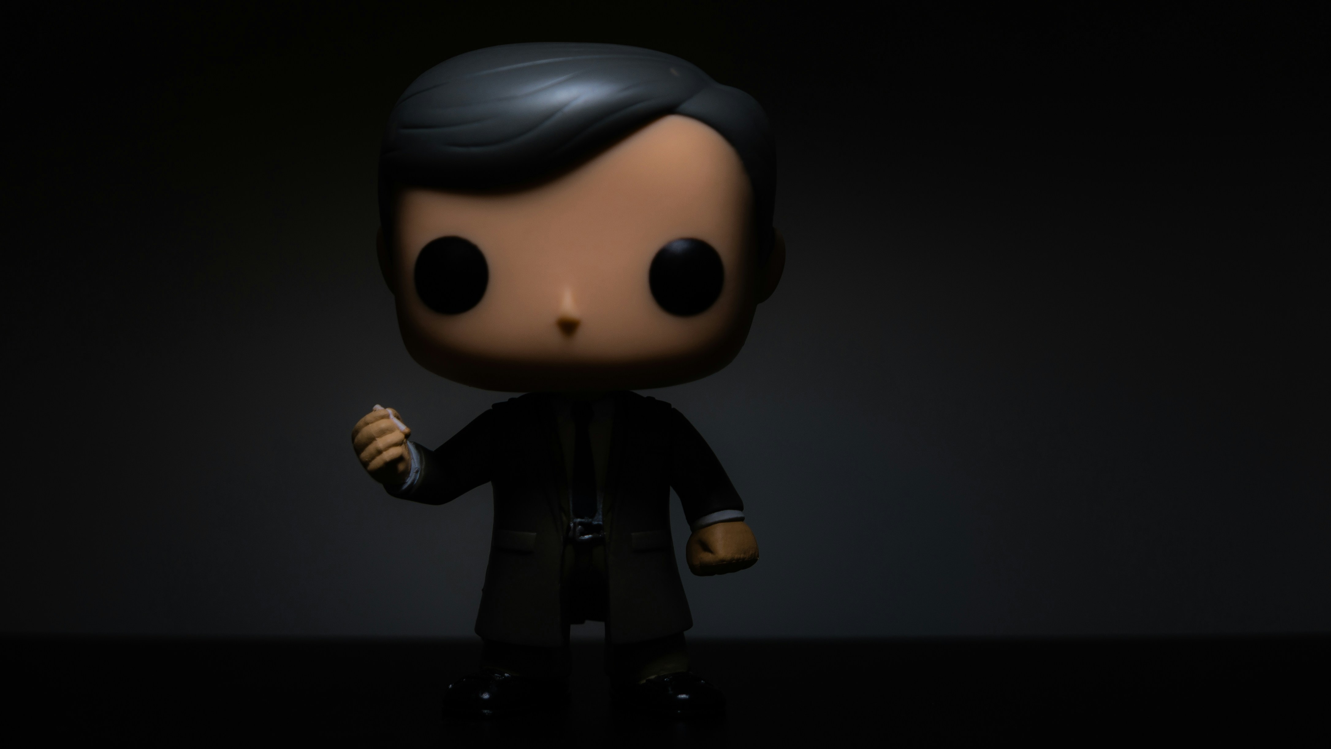 Vinyl figure of a man in a dark suit with minimal lighting.