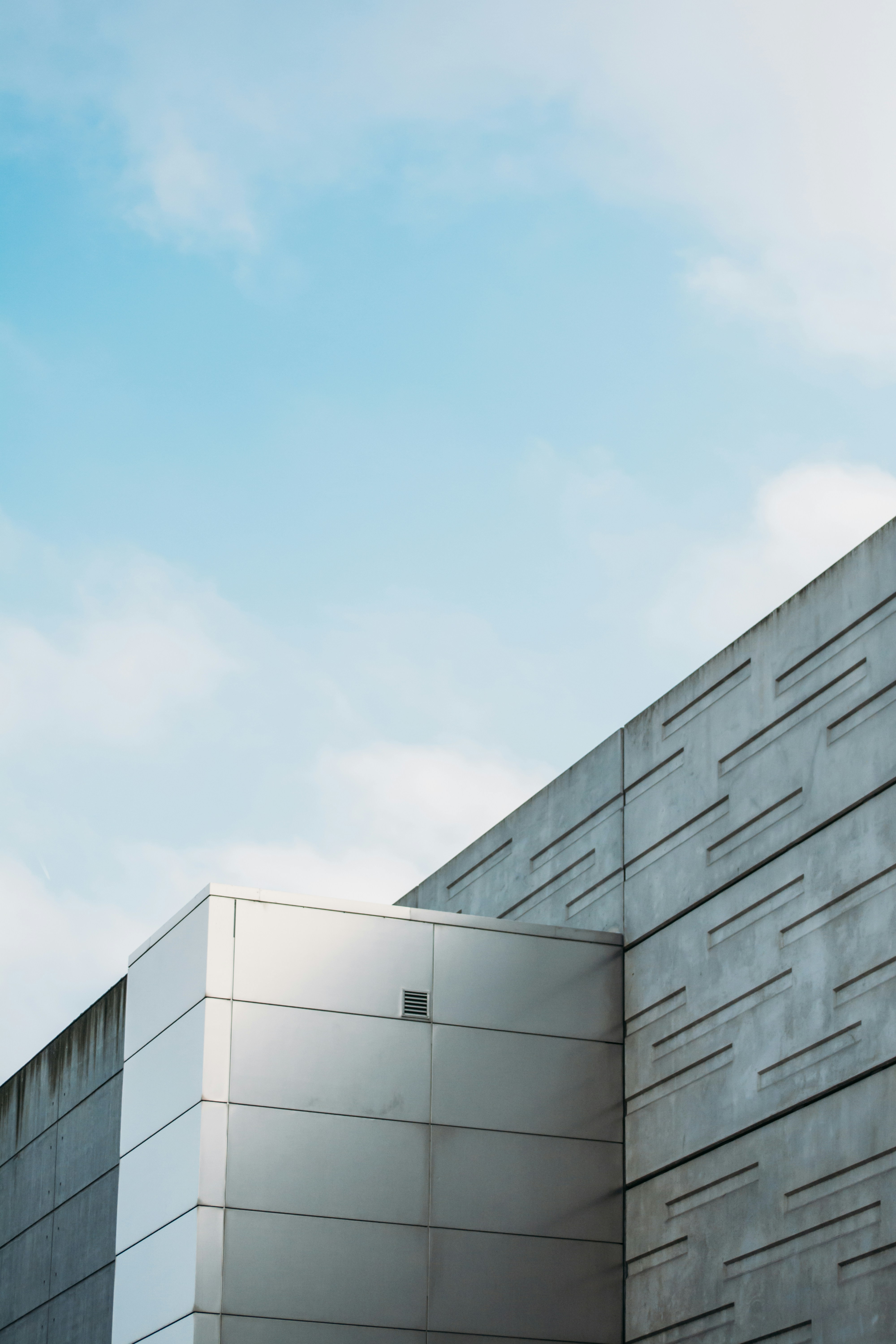Abstract architectural detail featuring a contrasting white and gray facade against a blue sky. Emphasizes clean lines and geometric shapes.