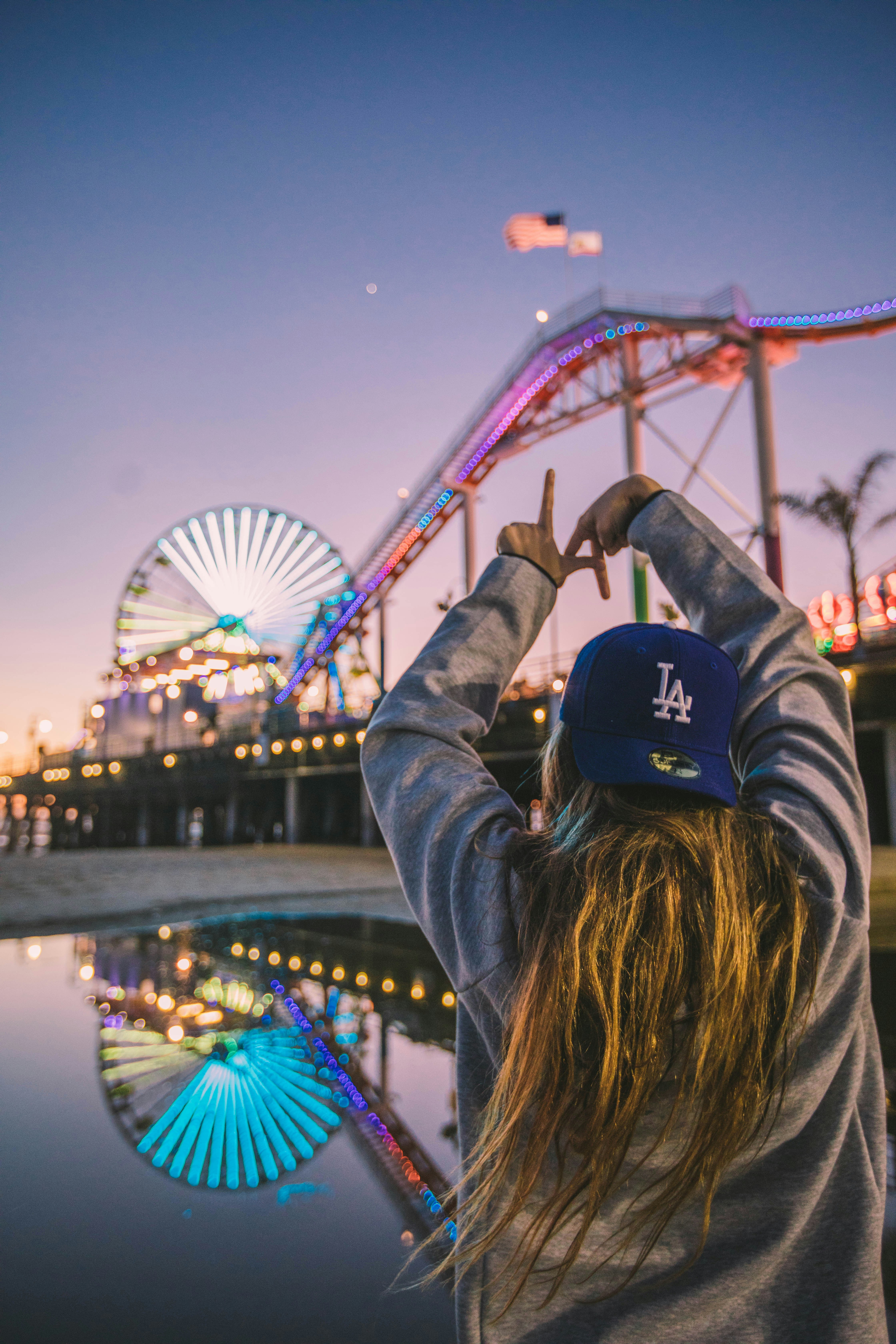 Neon Twilight Heart: Hands Raised Under Santa Monica Pier’s Night Arc