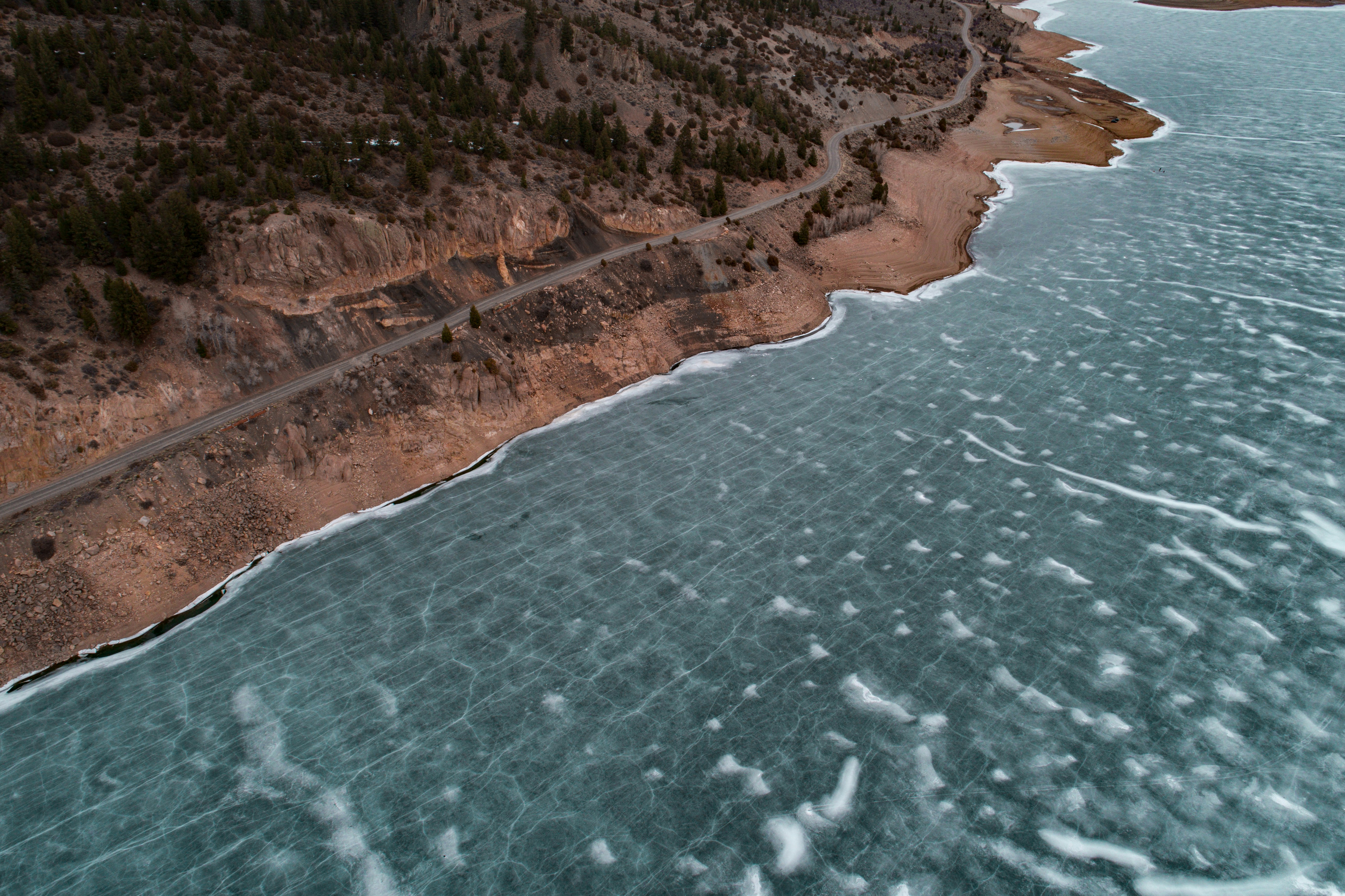 Aerial view of a winding shoreline meeting a rippling body of water, showcasing the interplay of land and aquatic textures.