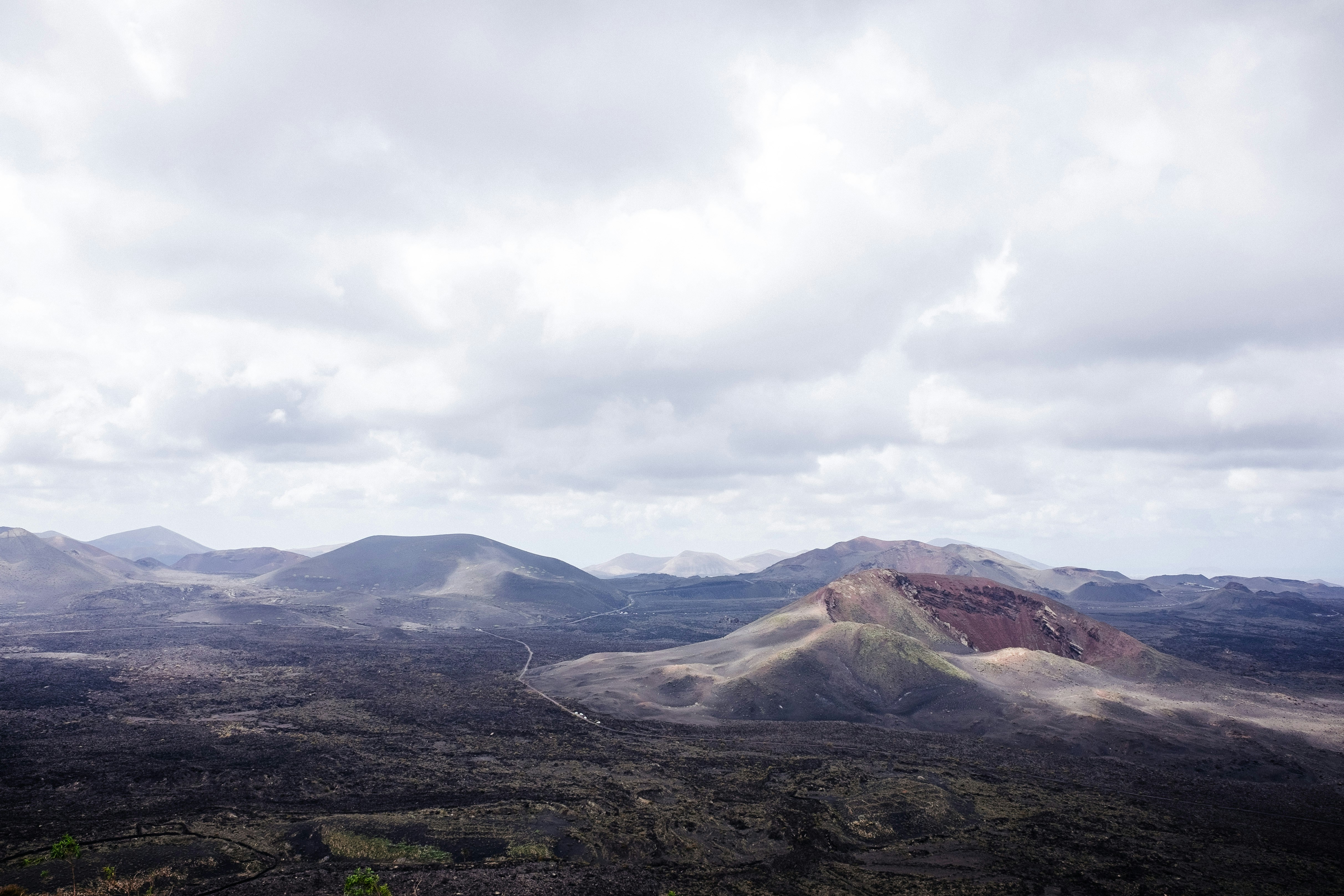 Vast mountainous landscape under a cloudy sky with hints of sunlight breaking through.