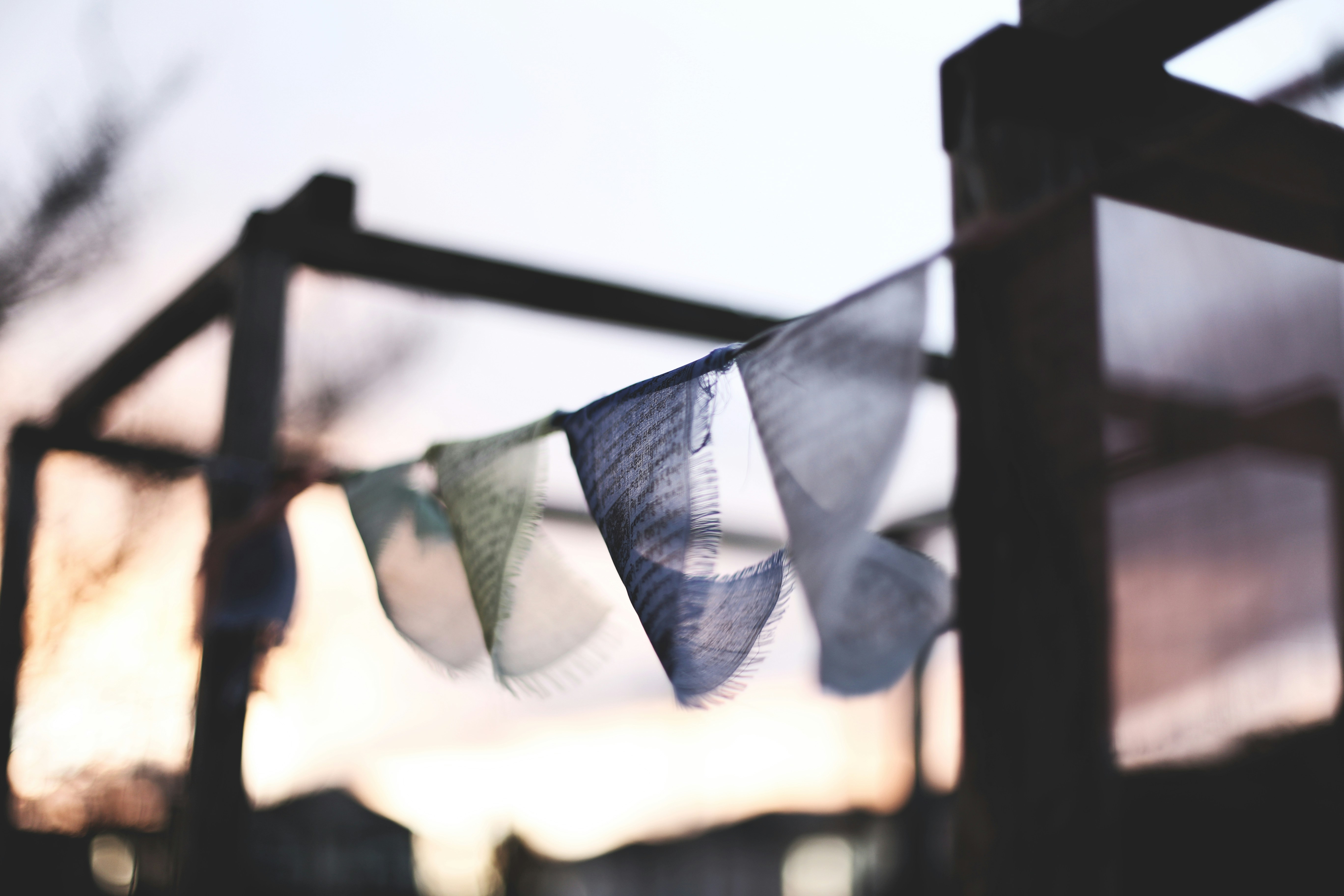 Colorful fabric prayer flags flutter gently against a twilight sky, creating a serene atmosphere. The delicate textures invite a sense of peace.