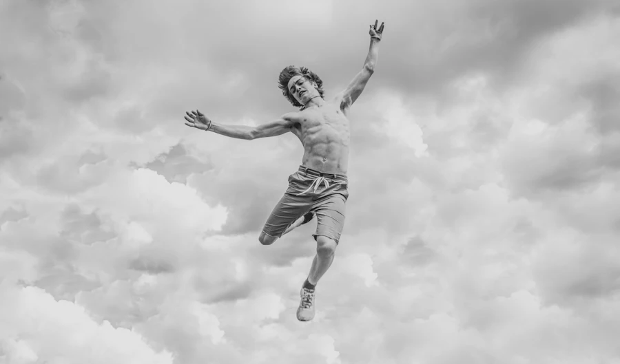 Theo Warden | grayscale photo of person jumping overlooking clouds