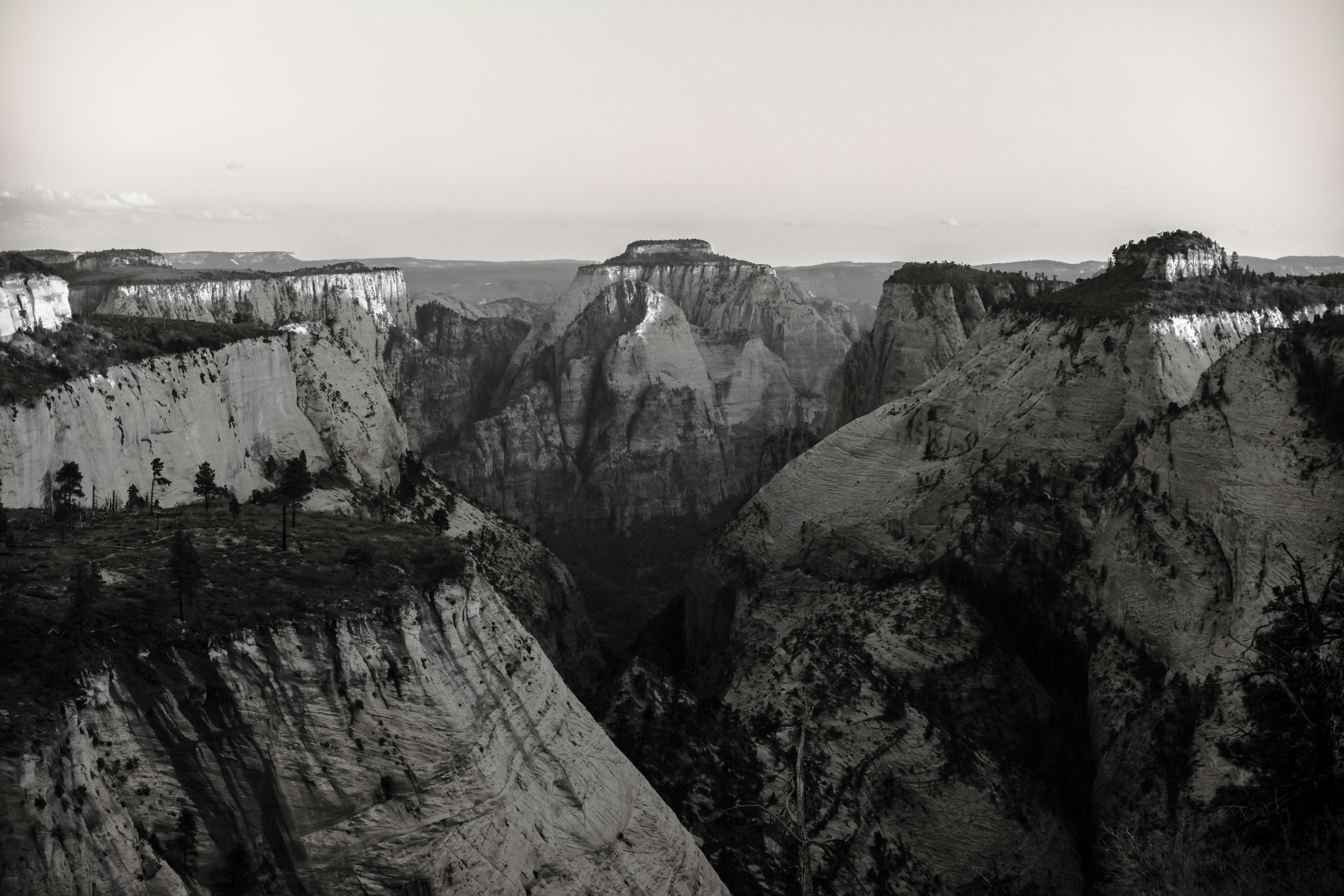 Monochrome landscape showcasing the dramatic contours of a canyon, with towering cliffs and deep ravines. The stark contrasts highlight the rugged beauty of the terrain.