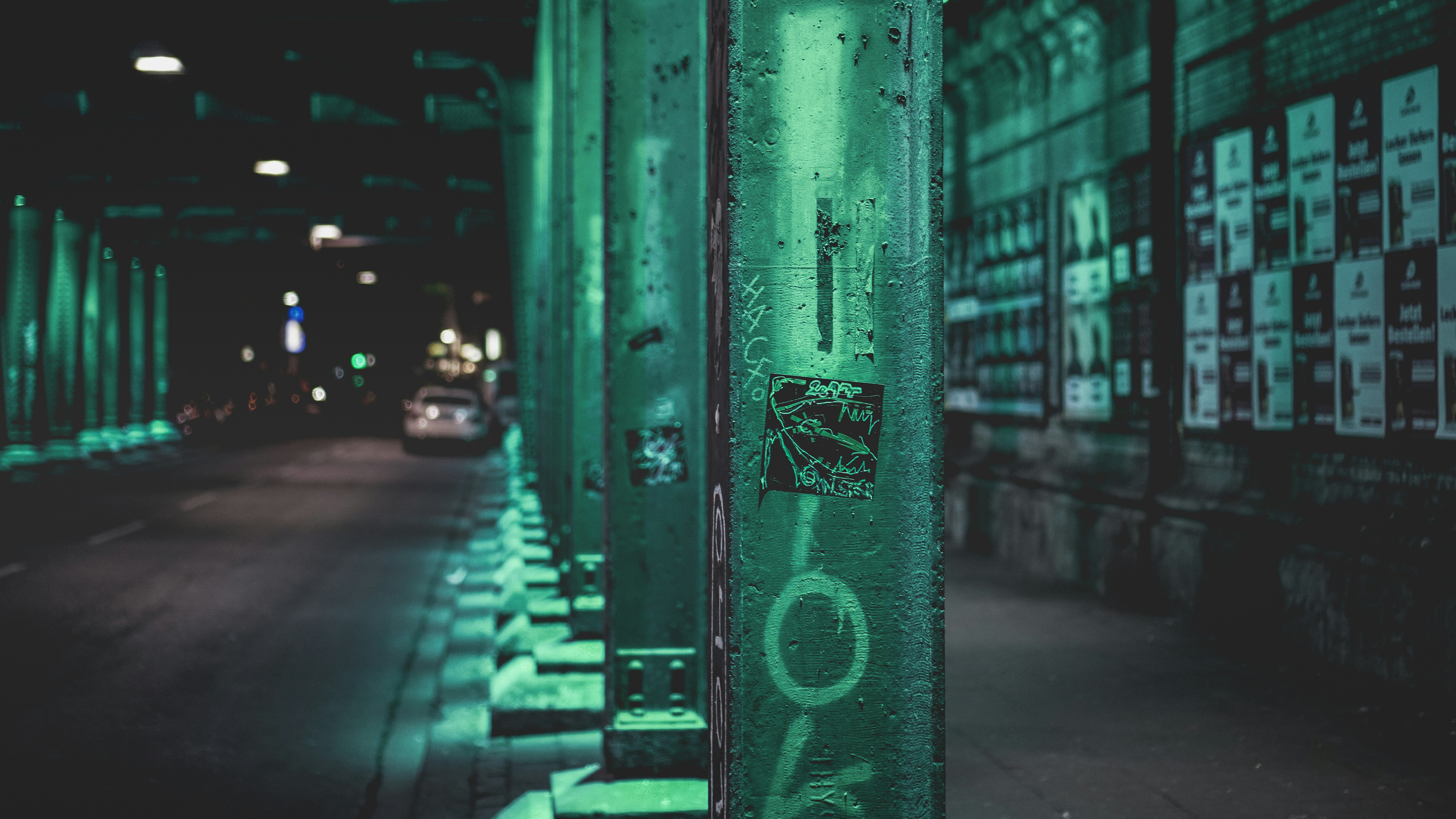 Urban bridge with green lights illuminating steel beams, creating a moody nighttime scene.