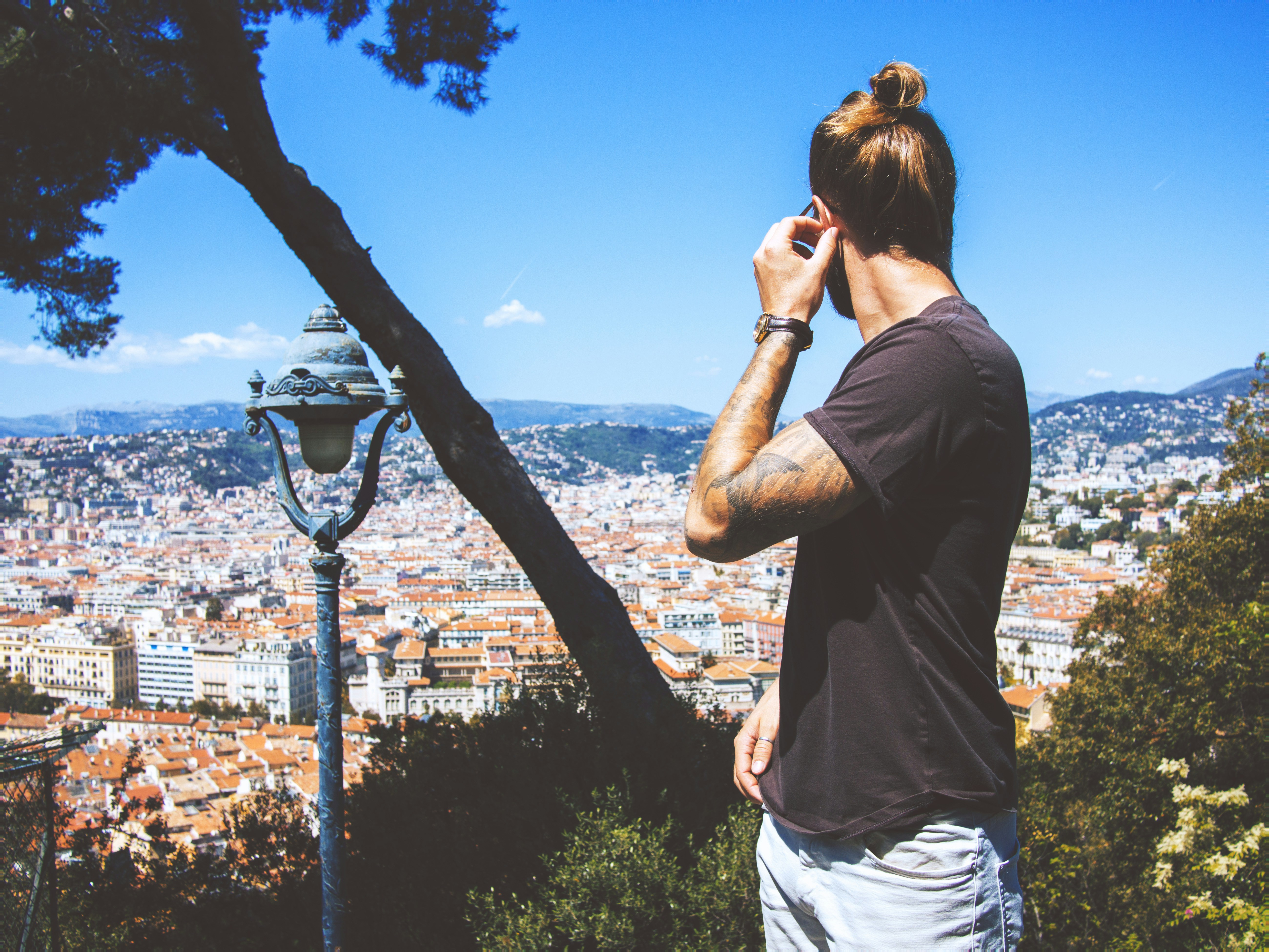 Person with a bun hairstyle gazing over a sprawling cityscape under a clear blue sky.