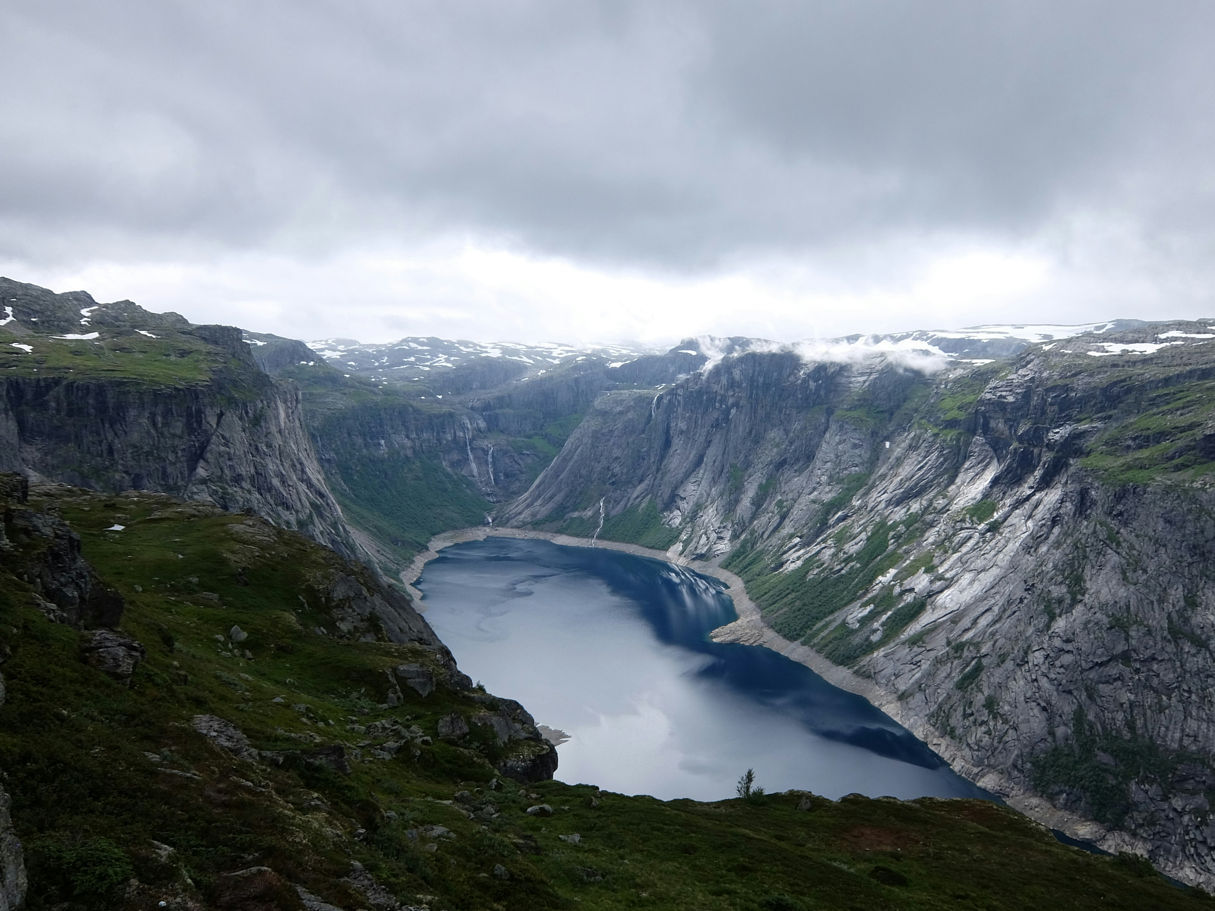 Majestic fjord surrounded by towering cliffs under a moody, overcast sky.
