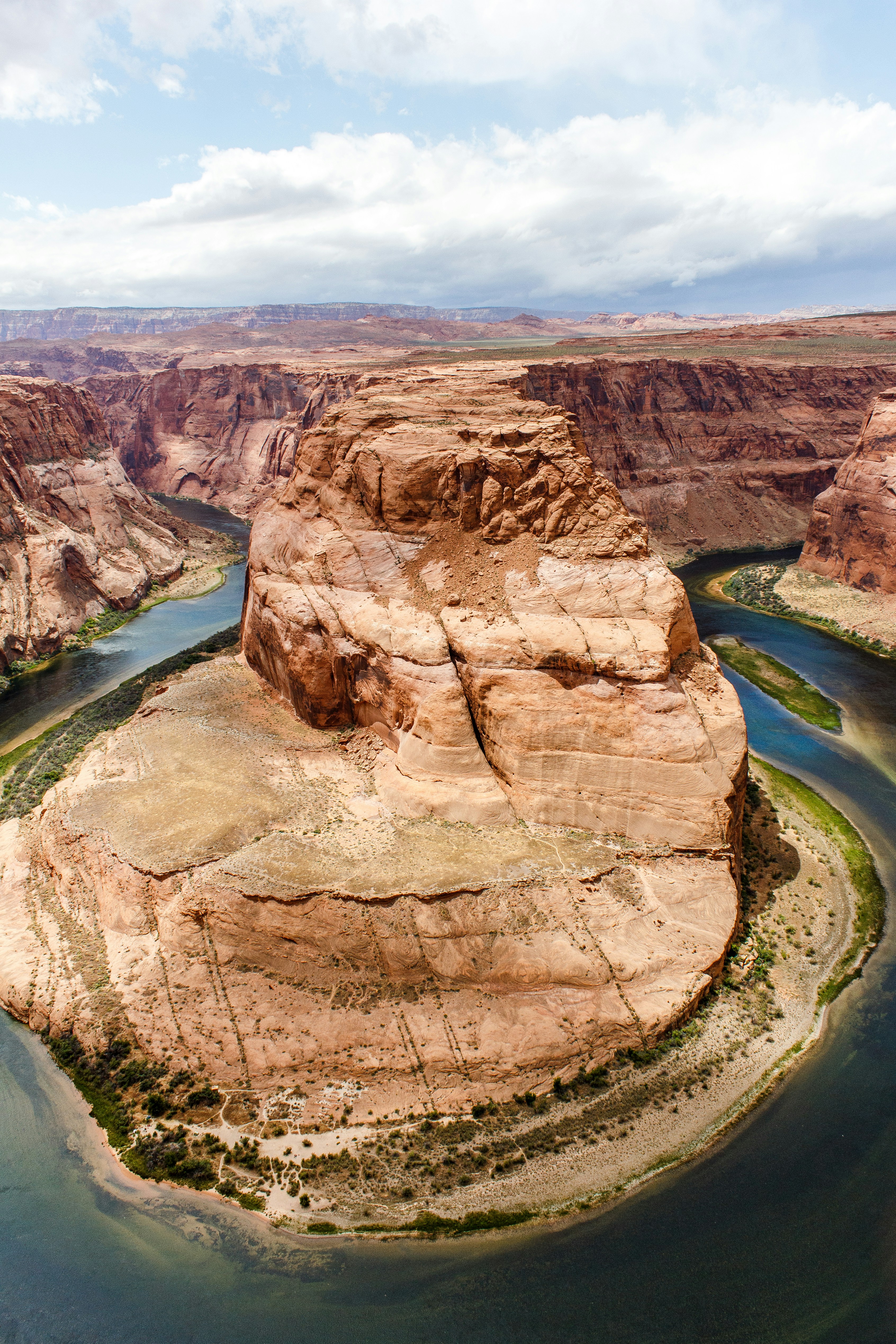 Aerial view of Horseshoe Bend, showcasing the dramatic curves of the Colorado River surrounded by red rock formations. The scene highlights the unique geological features of the landscape.