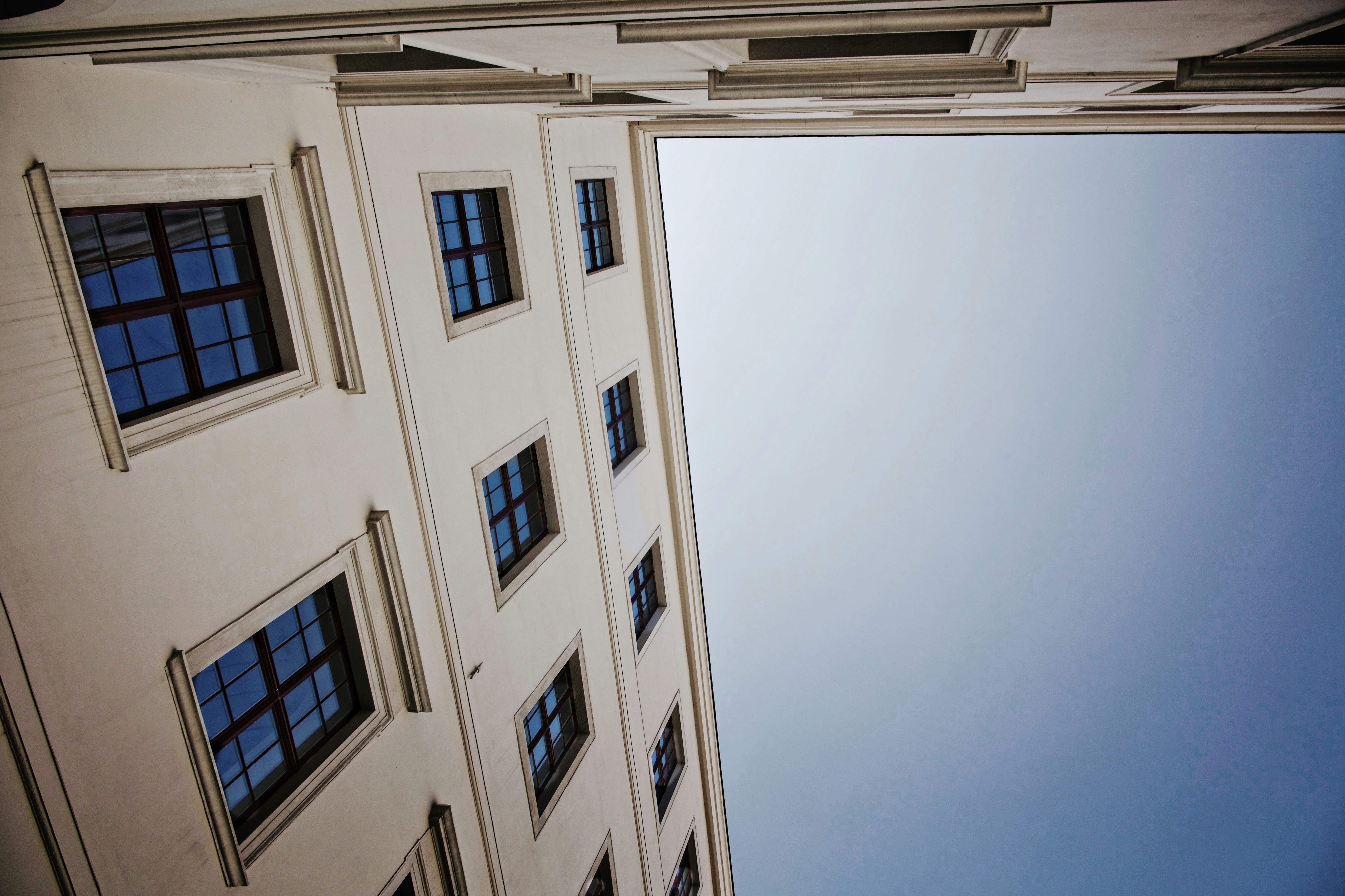 Tall building facade with symmetrical windows stretching towards a clear blue sky.