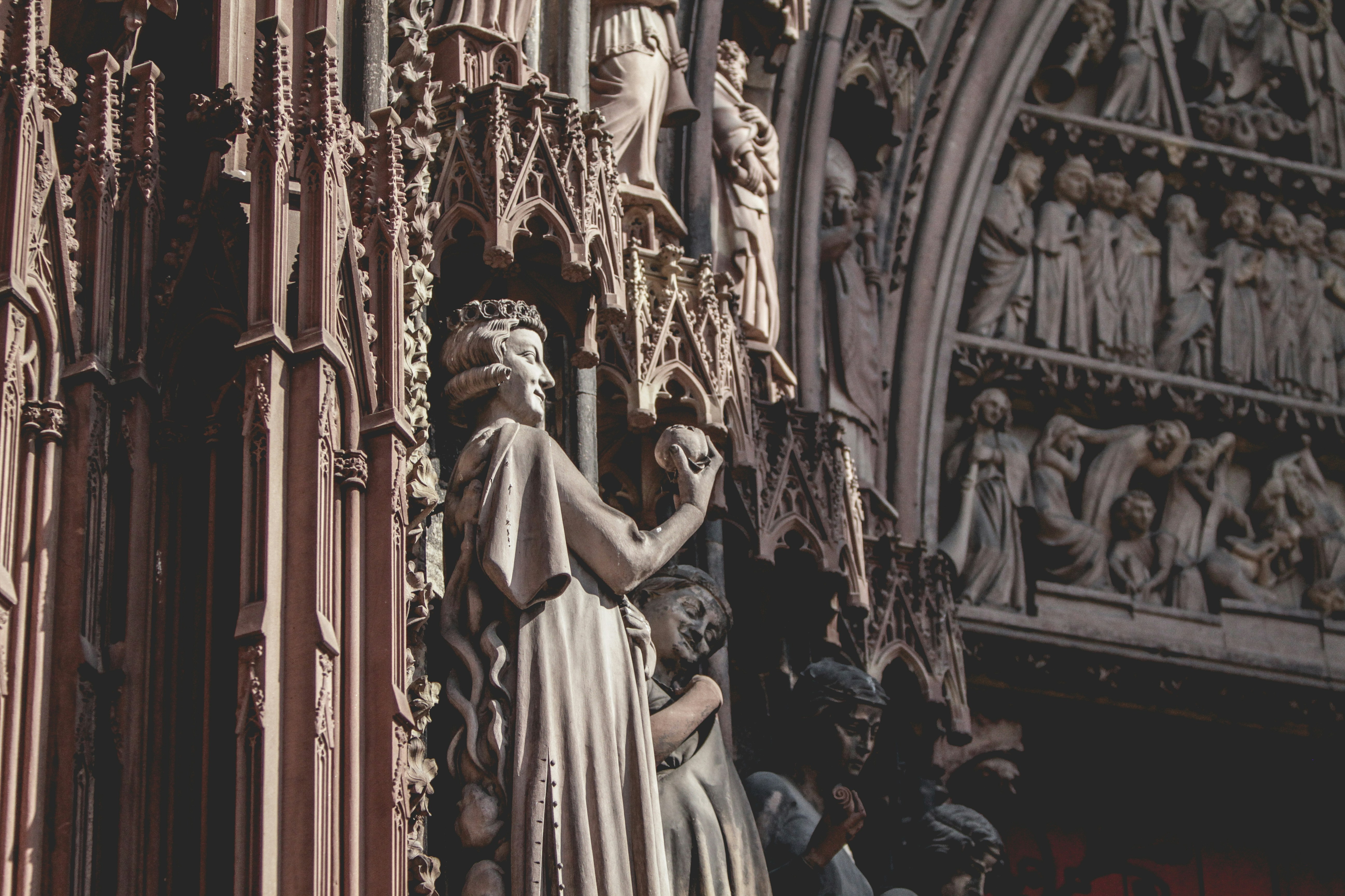 Stone statues of a woman and child intricately carved into a cathedral wall adorned with detailed figures.