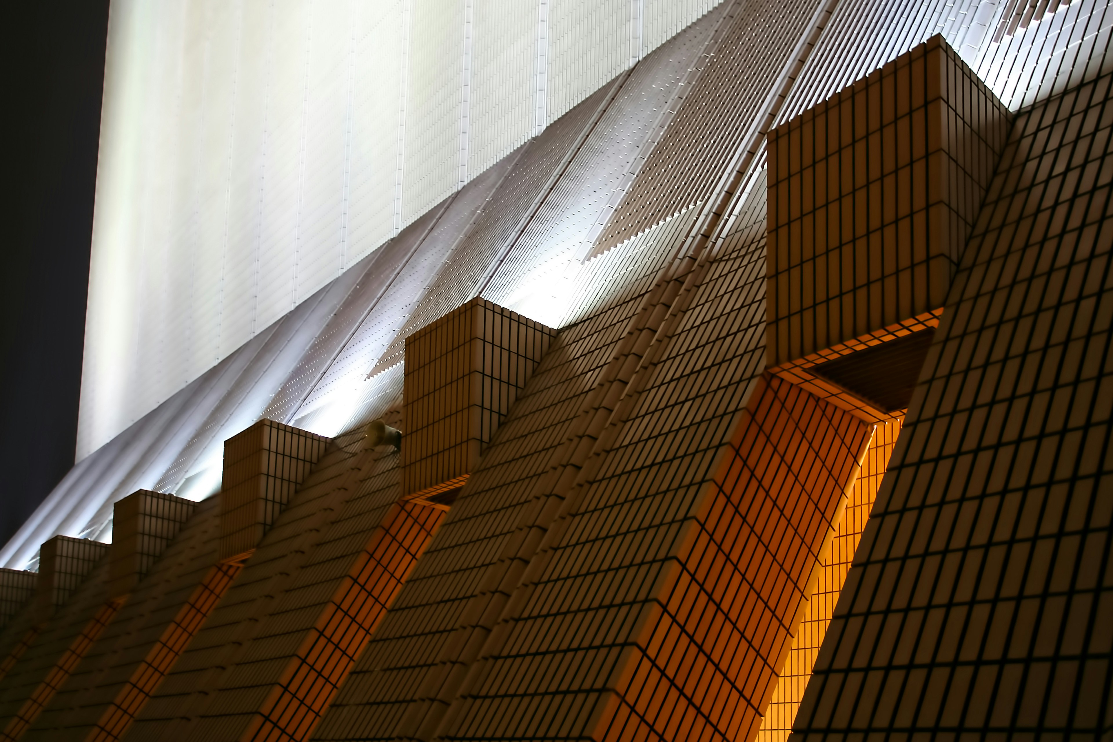 Abstract architectural structure featuring illuminated geometric forms and textured surfaces against a dark background.
