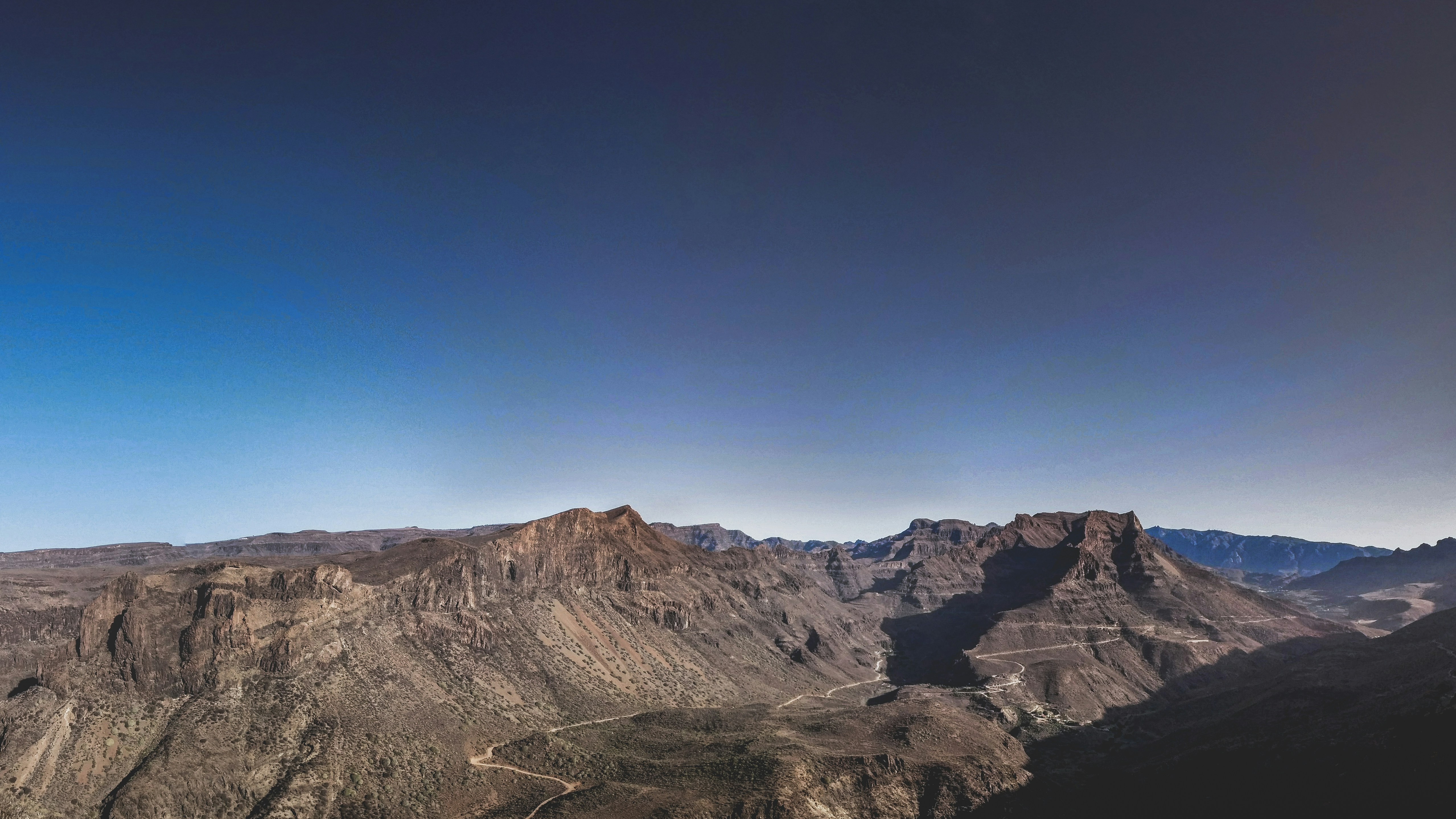 Expansive view of rocky mountains under a clear blue sky in Gran Canaria during daytime.