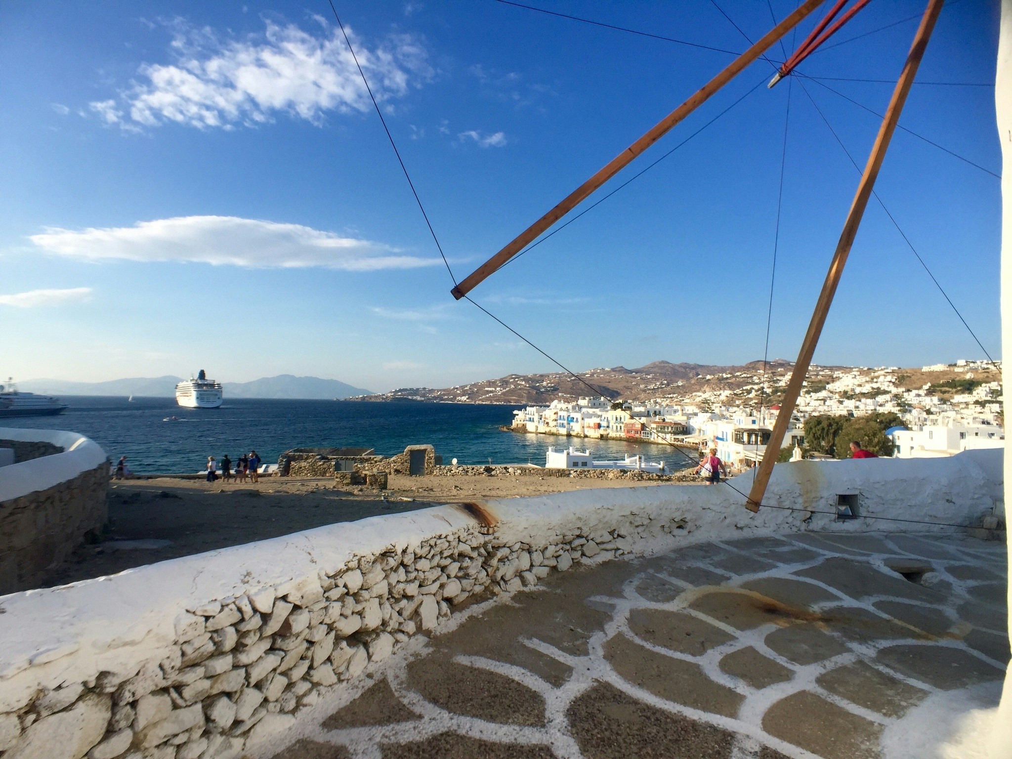 Aegean Harbor Vista: Whitewashed Promenade, Blue Sea, and a Leaning Mast