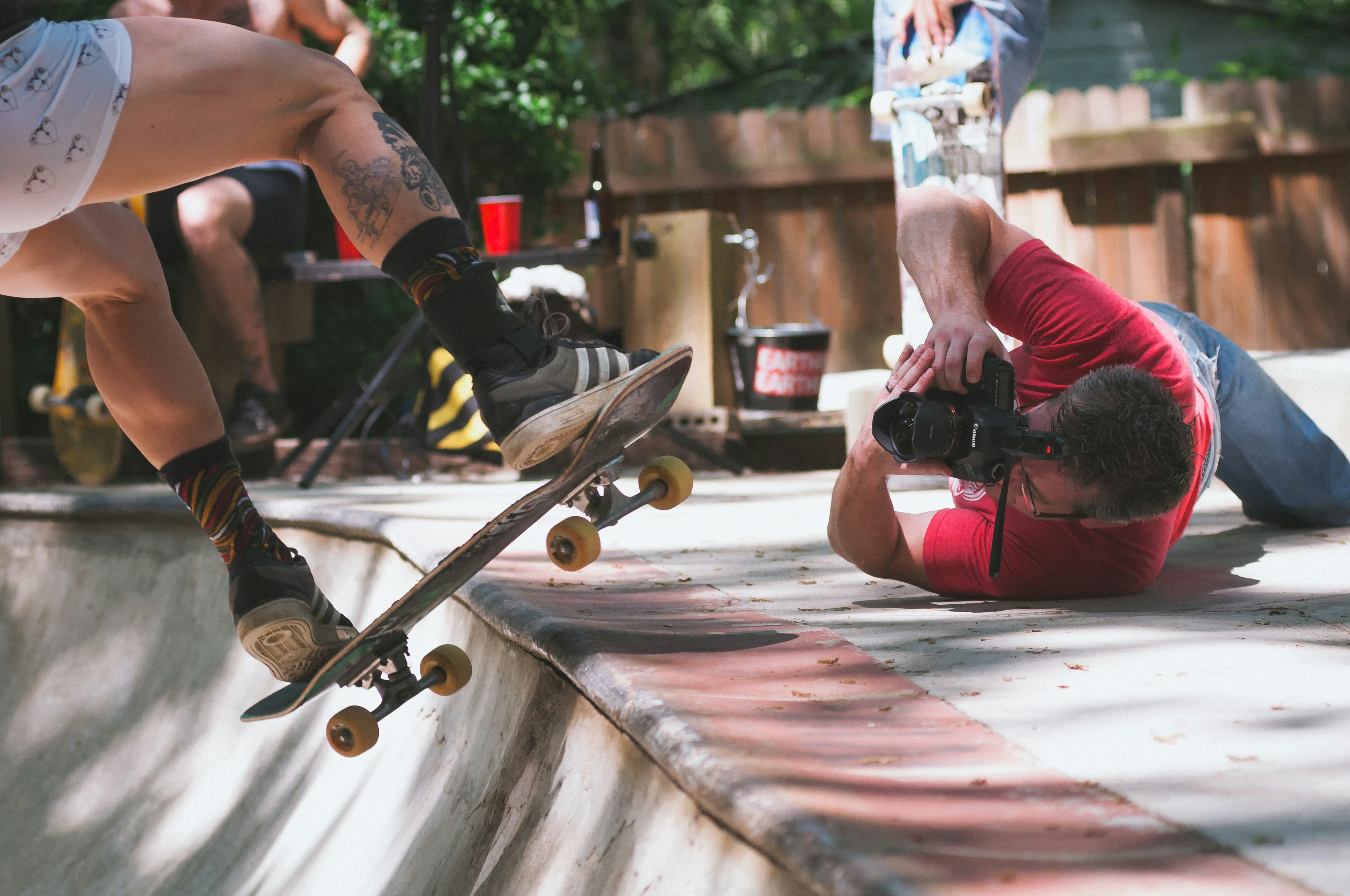 Skateboarder performing a trick on a ramp while a photographer captures the moment up close.