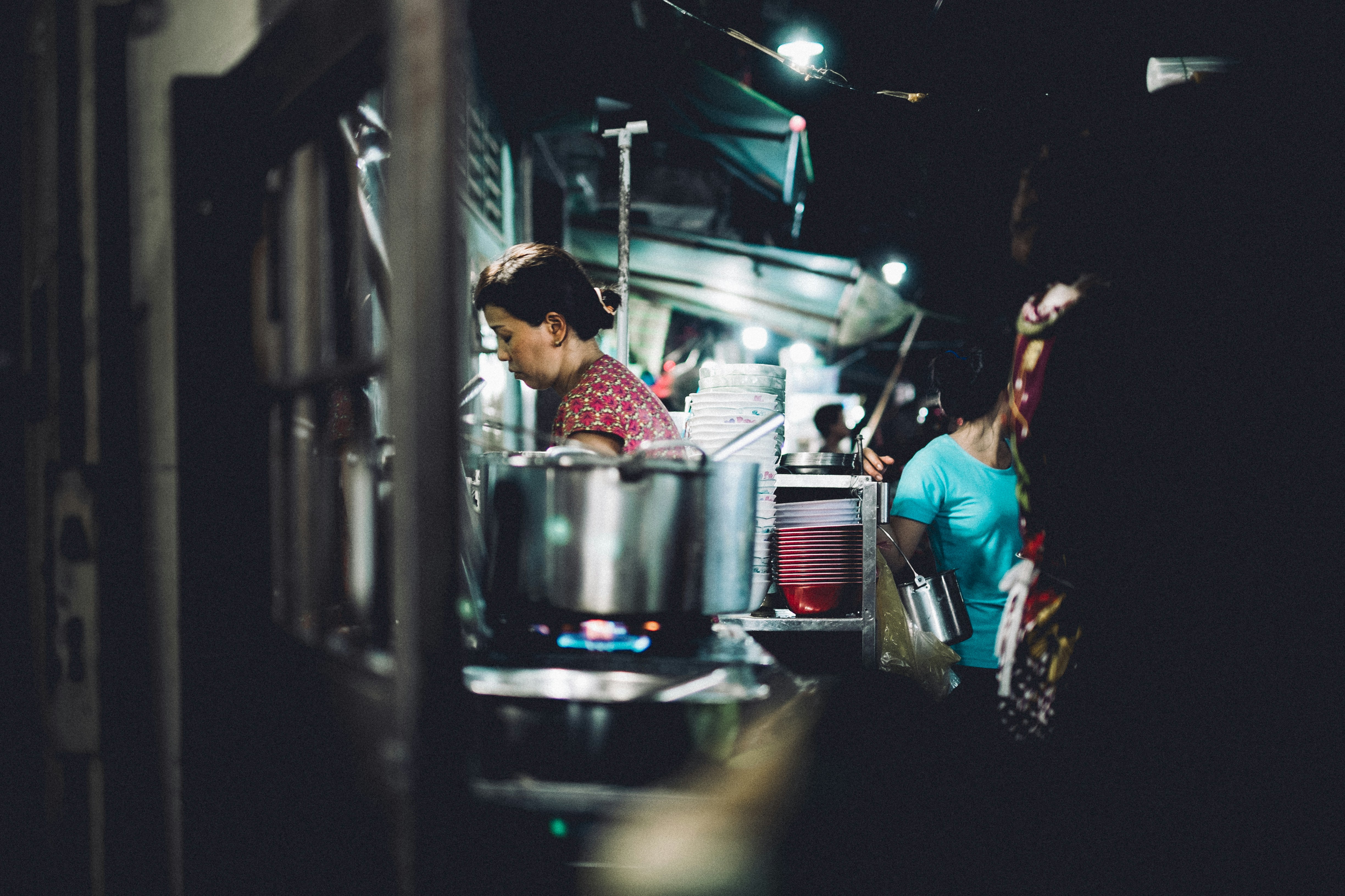 Street vendor preparing food in a dimly lit Saigon alley at night.