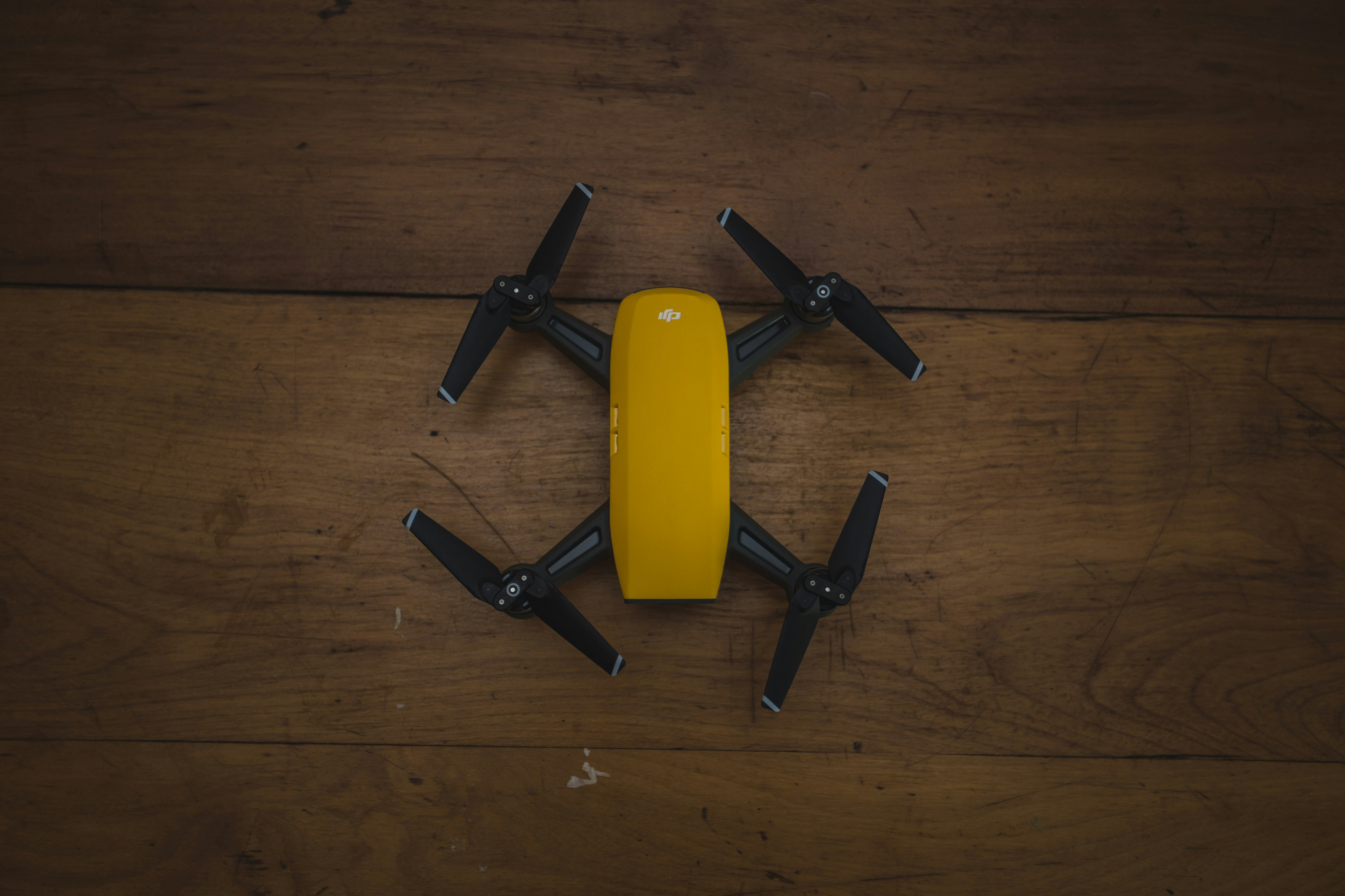 Yellow drone resting on a wooden surface, showcasing its sleek design and modern technology.