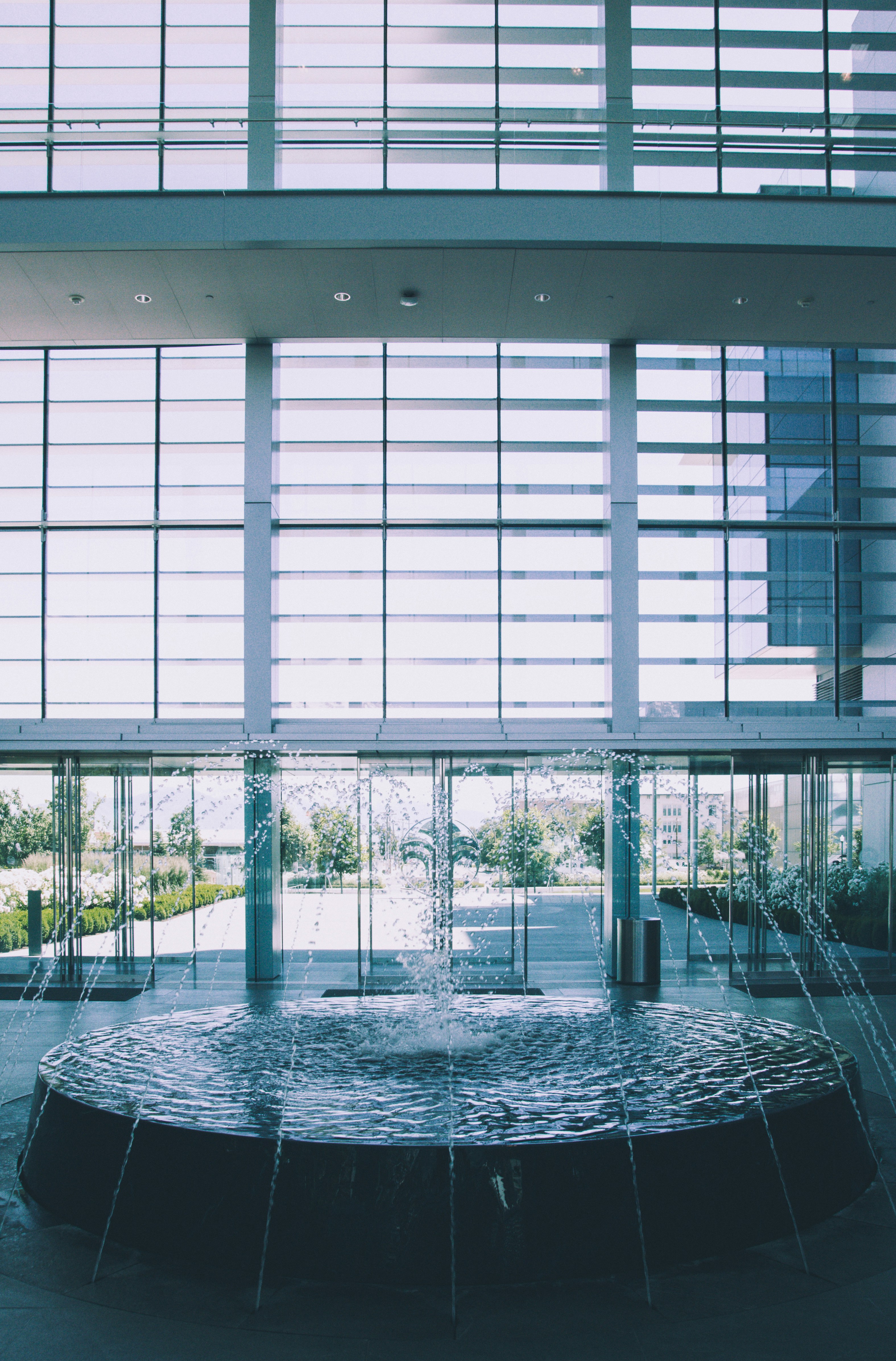Symmetry in Glass Atrium: Circular Fountain Under a Grid of Windows
