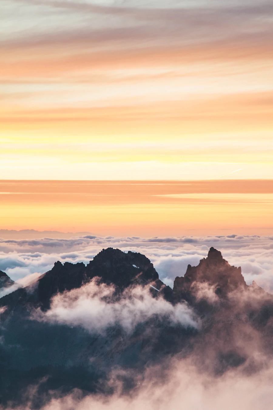 Sun sets over cloud-shrouded peaks | top view of mountain covered by clouds