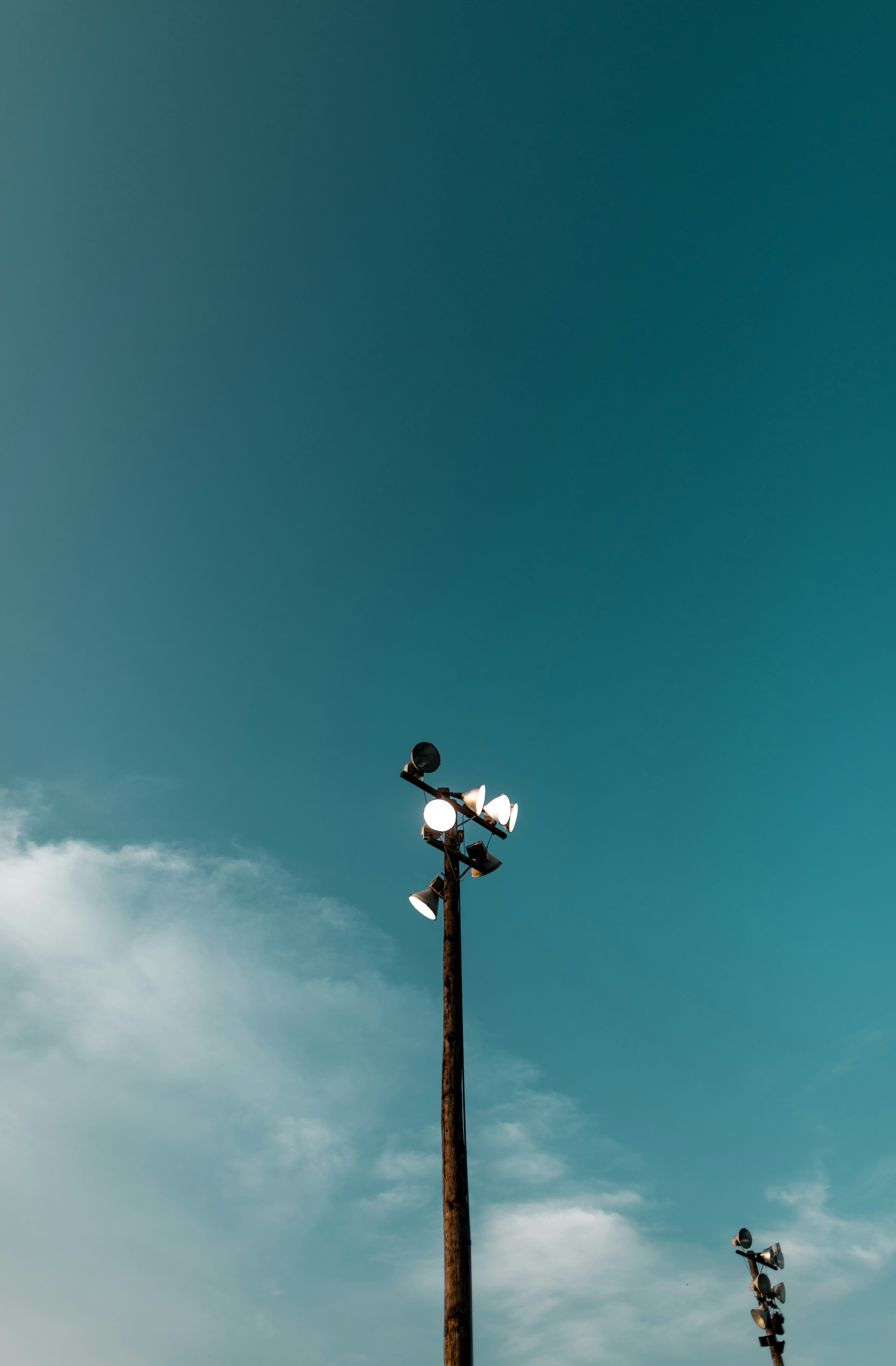 Tall wooden poles adorned with floodlights rise against a clear blue sky, capturing the essence of outdoor illumination.