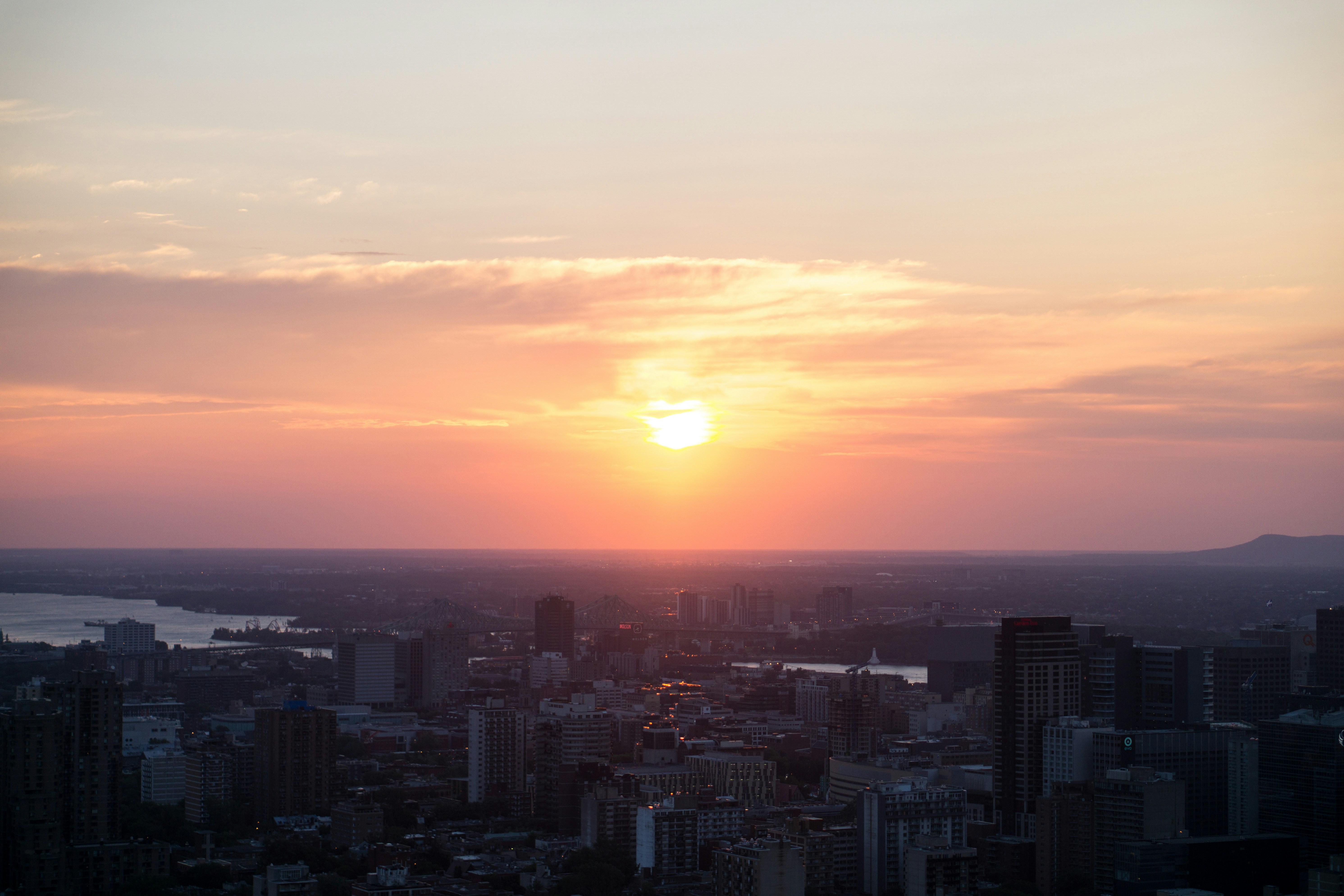 Sun rising over a city skyline with a warm gradient sky and silhouetted buildings.