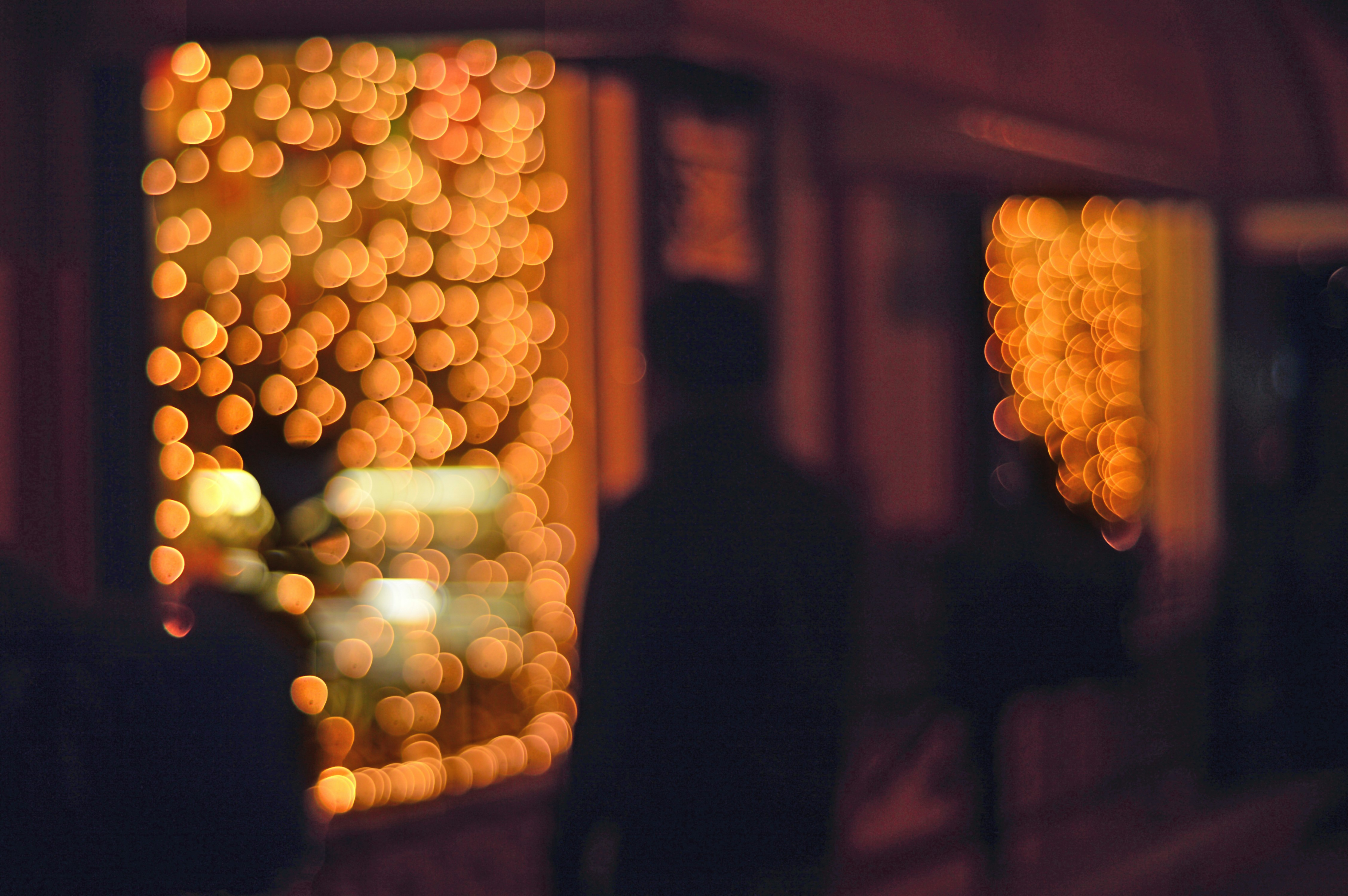 Soft focus on warm yellow lights illuminating a restaurant window at night.