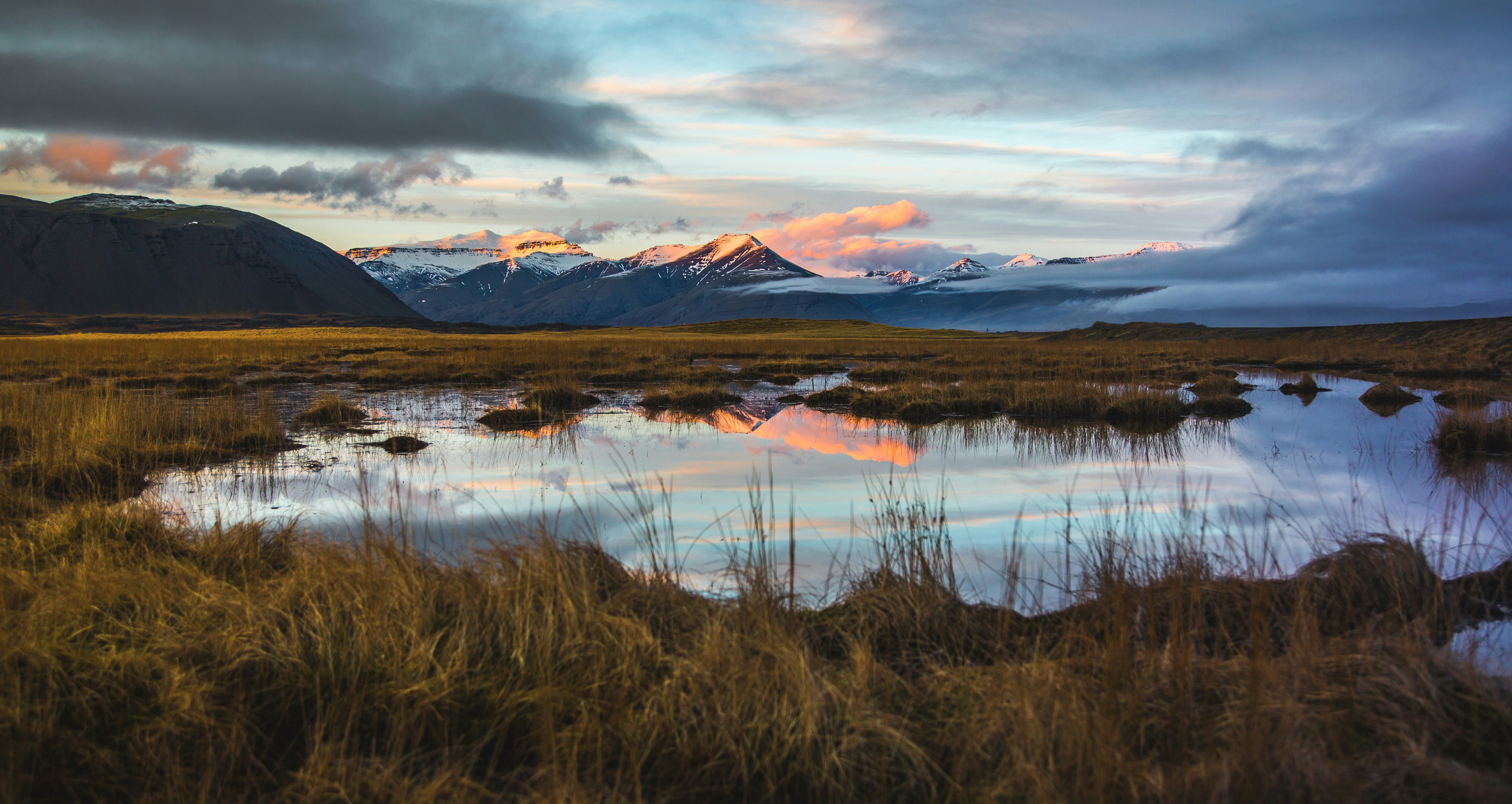 Just before dusk on the drive back to our accommodation, we saw this beautiful sunset reflected off the water. | body of water between grass field far from mountain