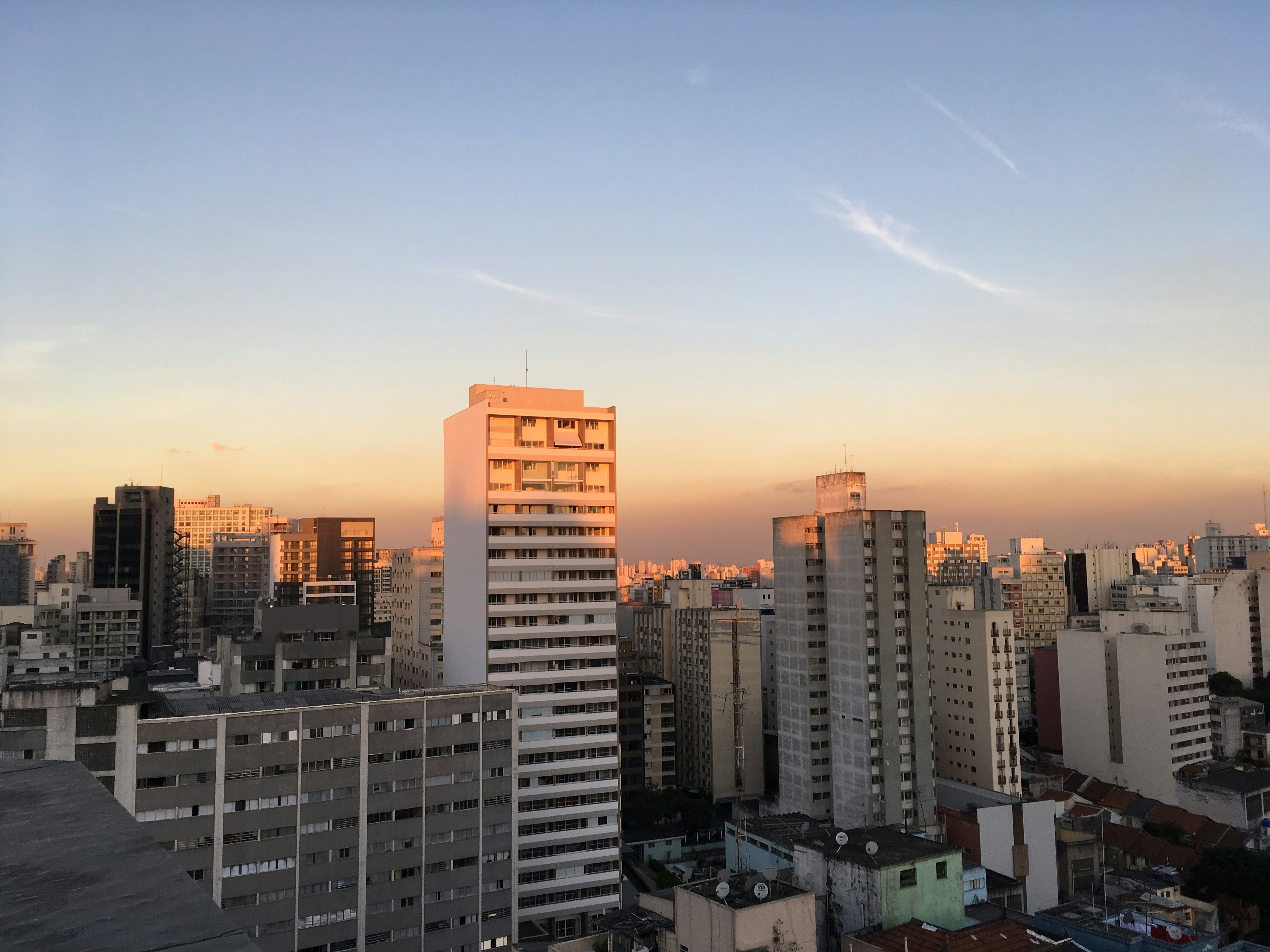 City skyline at sunrise with soft orange hues illuminating the buildings.