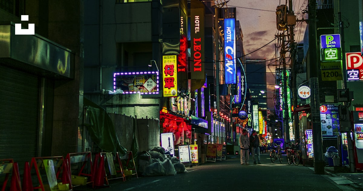 야간에 건물 사이의 콘크리트 도로에 서 있는 두 사람 사진 Unsplash의 무료 도시 이미지