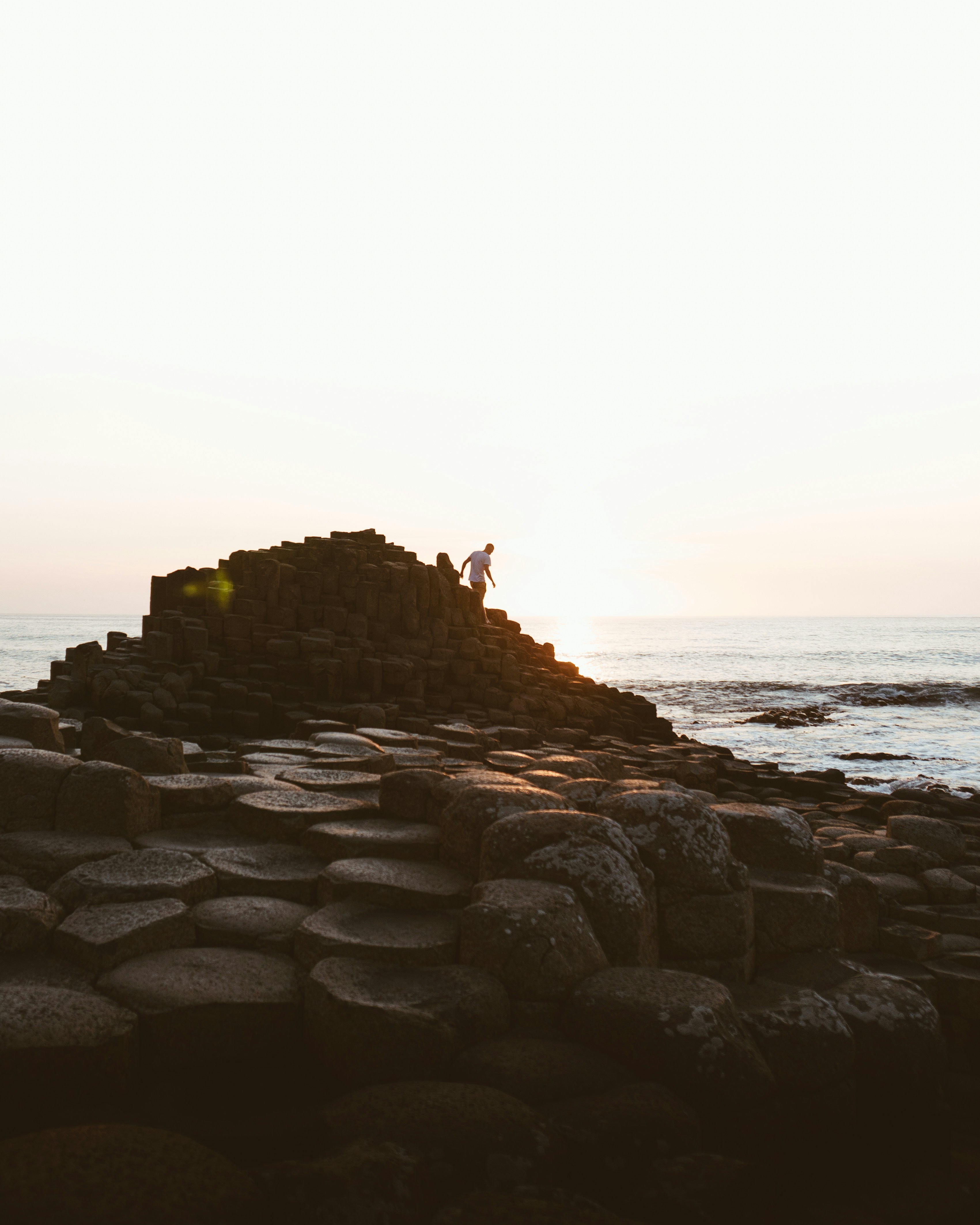 Hexagonal Summit: A Lone Climber at Sunset on the Giants' Causeway