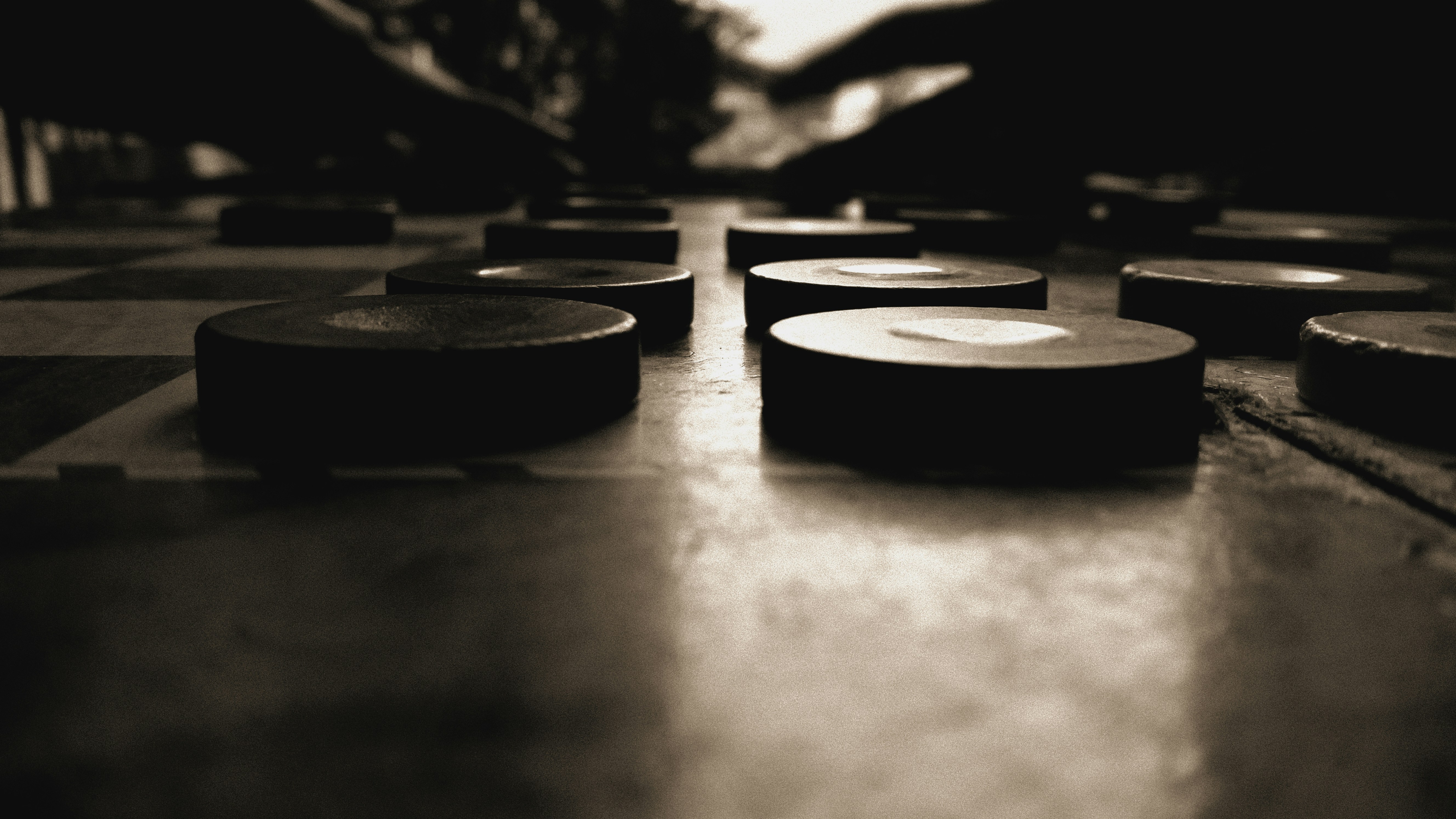 Low-angle view of checkers pieces in dramatic lighting on a game board.