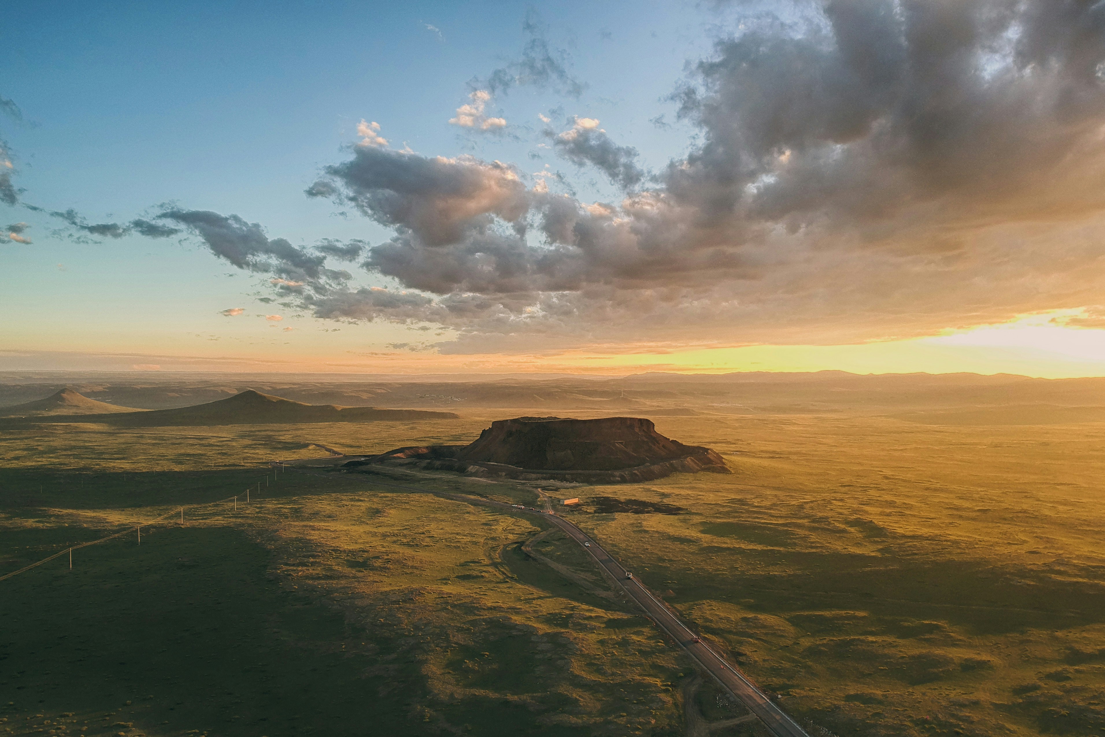 Volcanic landscape under dramatic skies at sunset.