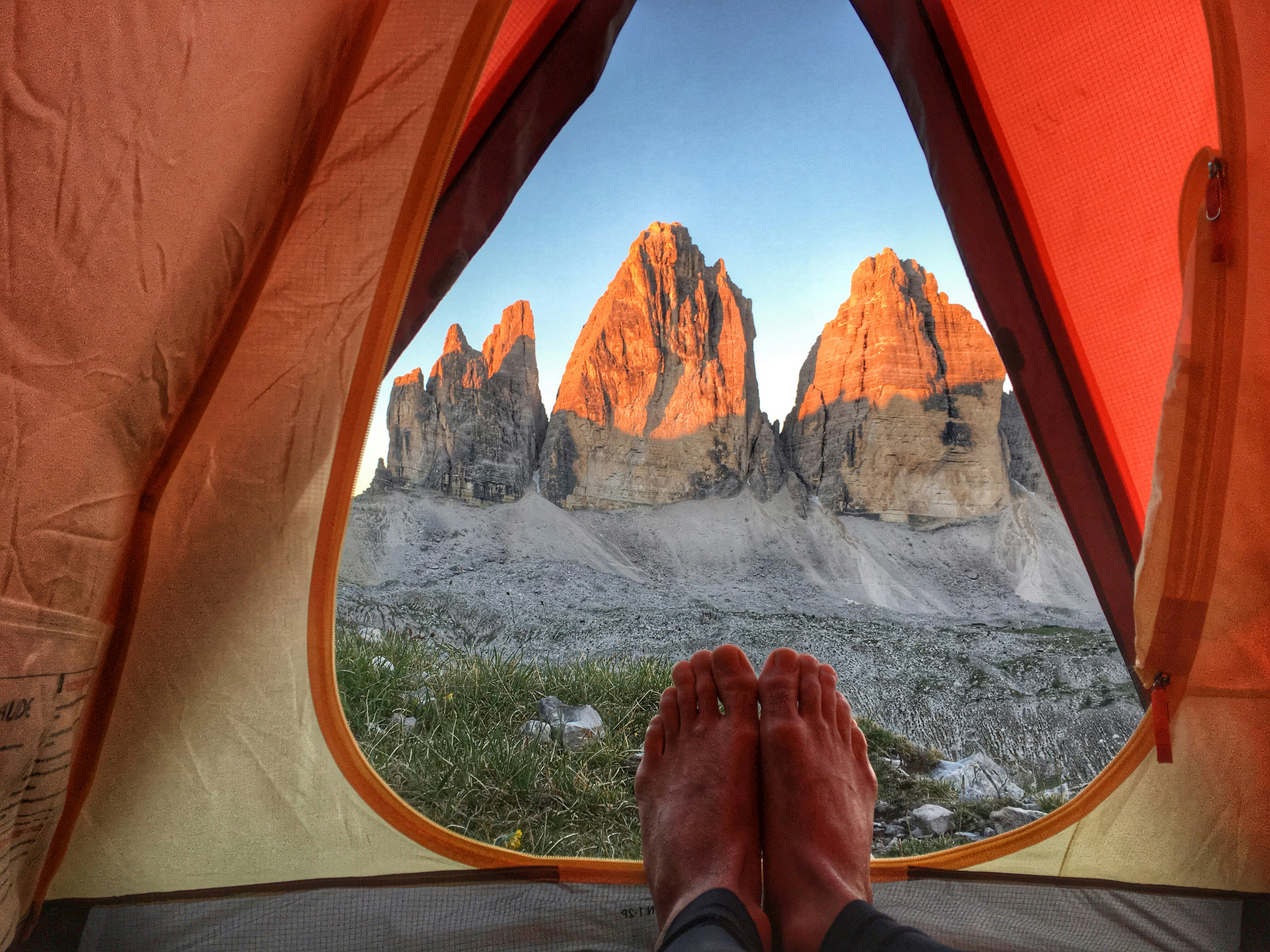 Three Peaks at Dawn Framed by a Warm Tent Opening