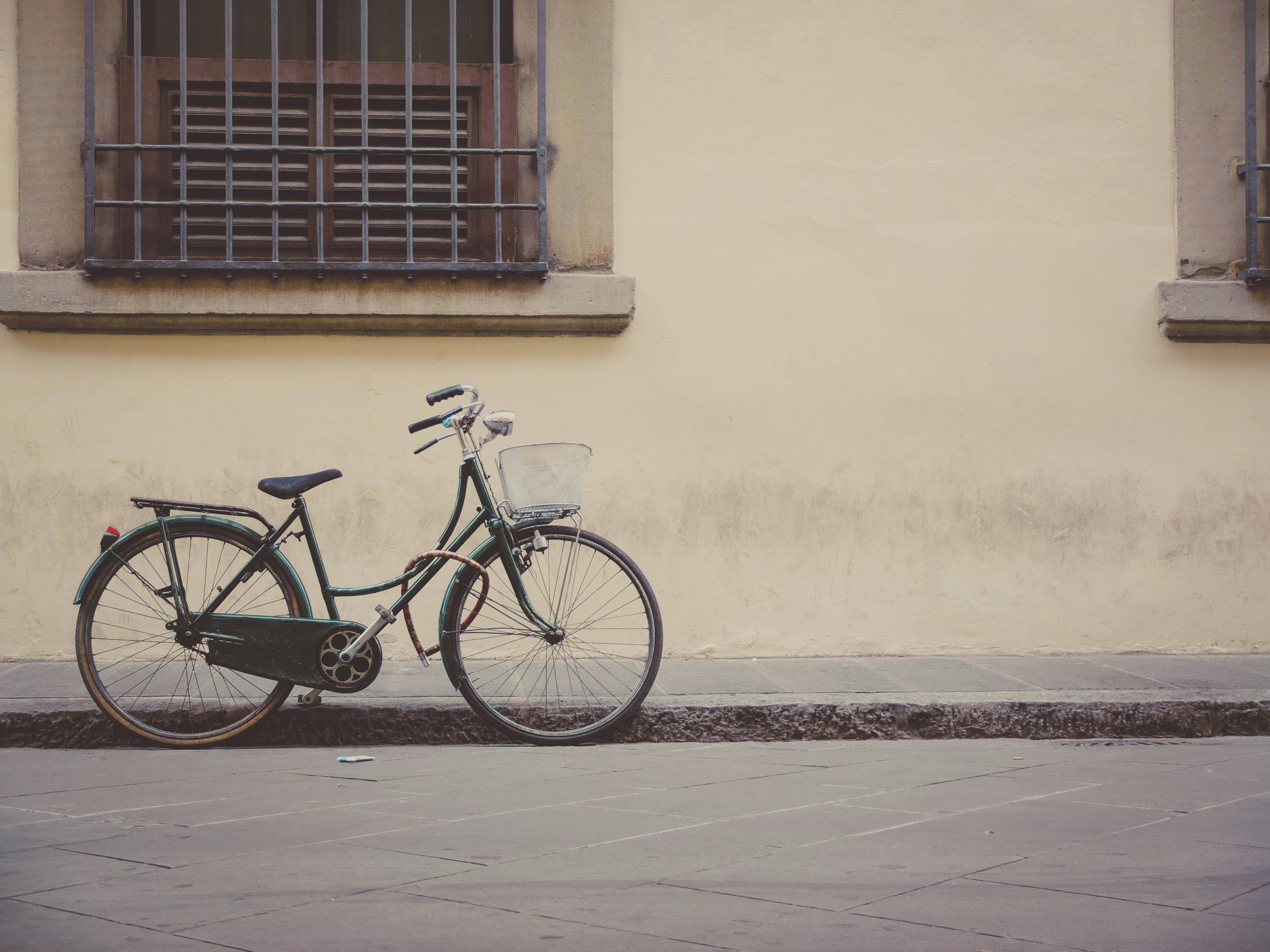 A vintage bicycle rests against a textured wall, showcasing its classic design and charm. The simplicity of the scene evokes nostalgia.