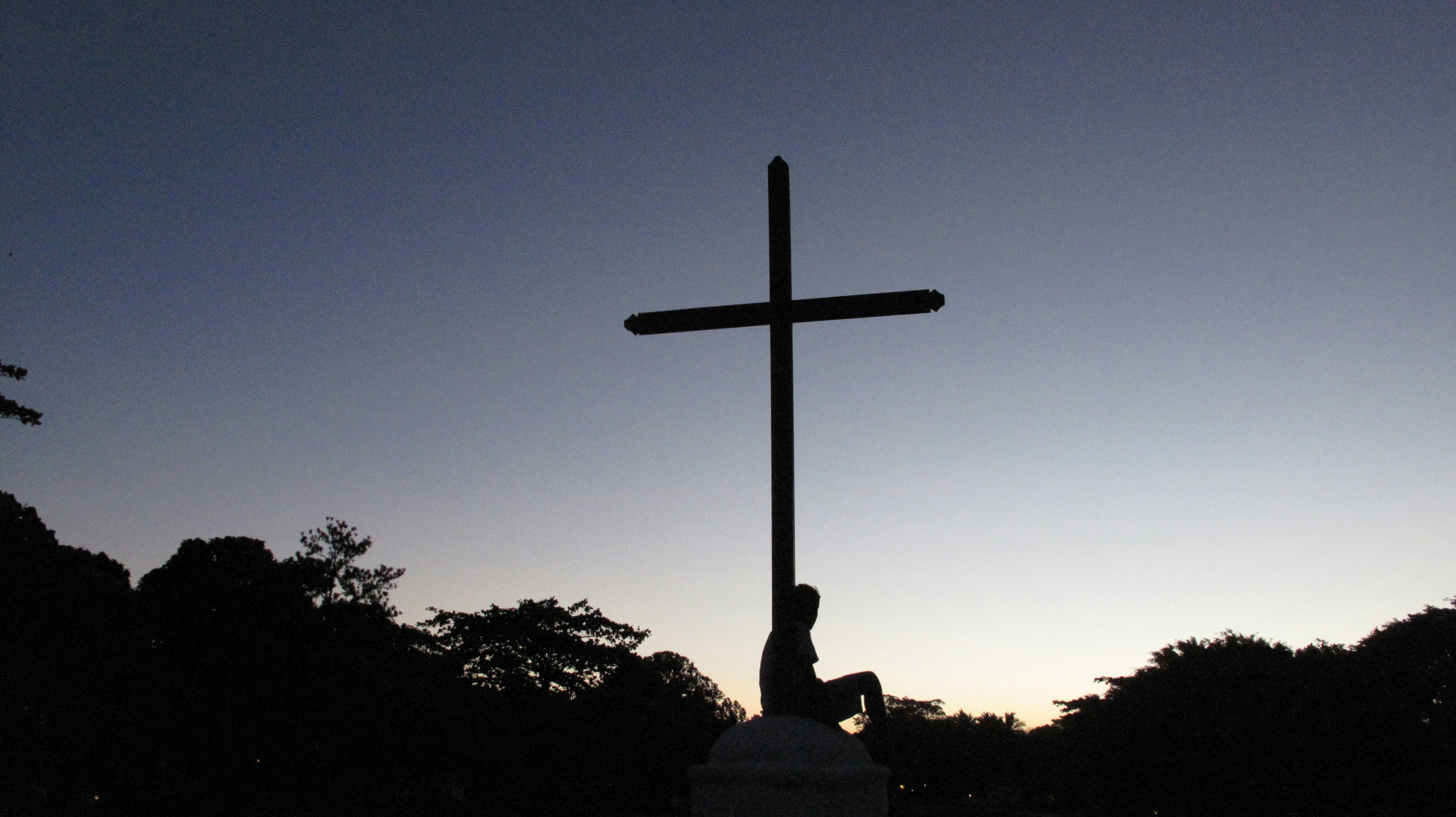 Shadow in Trancoso | silhouette of person sitting below cross