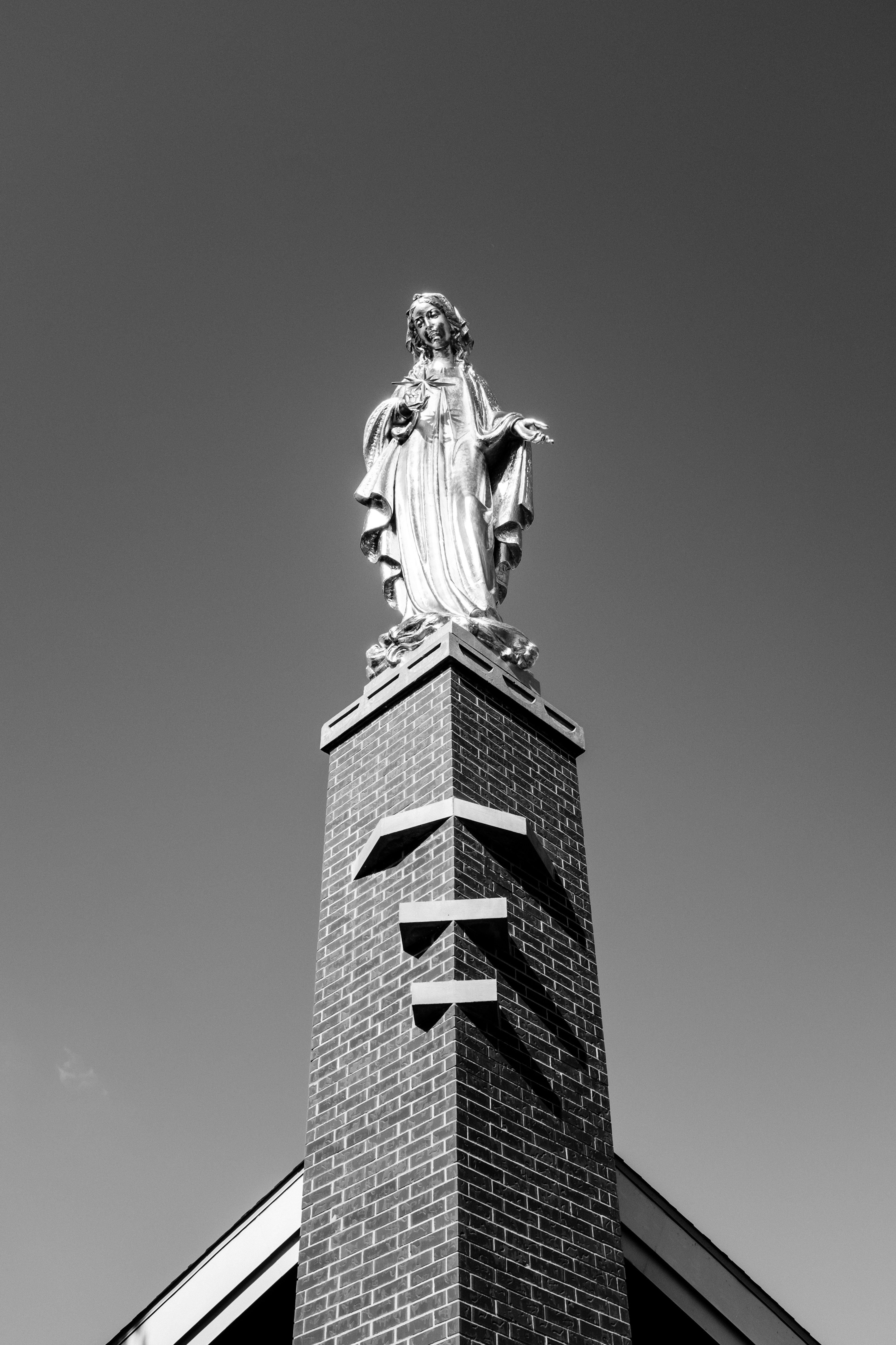 Solitary Statue Rising from a Brick Spire Under a Clear Sky