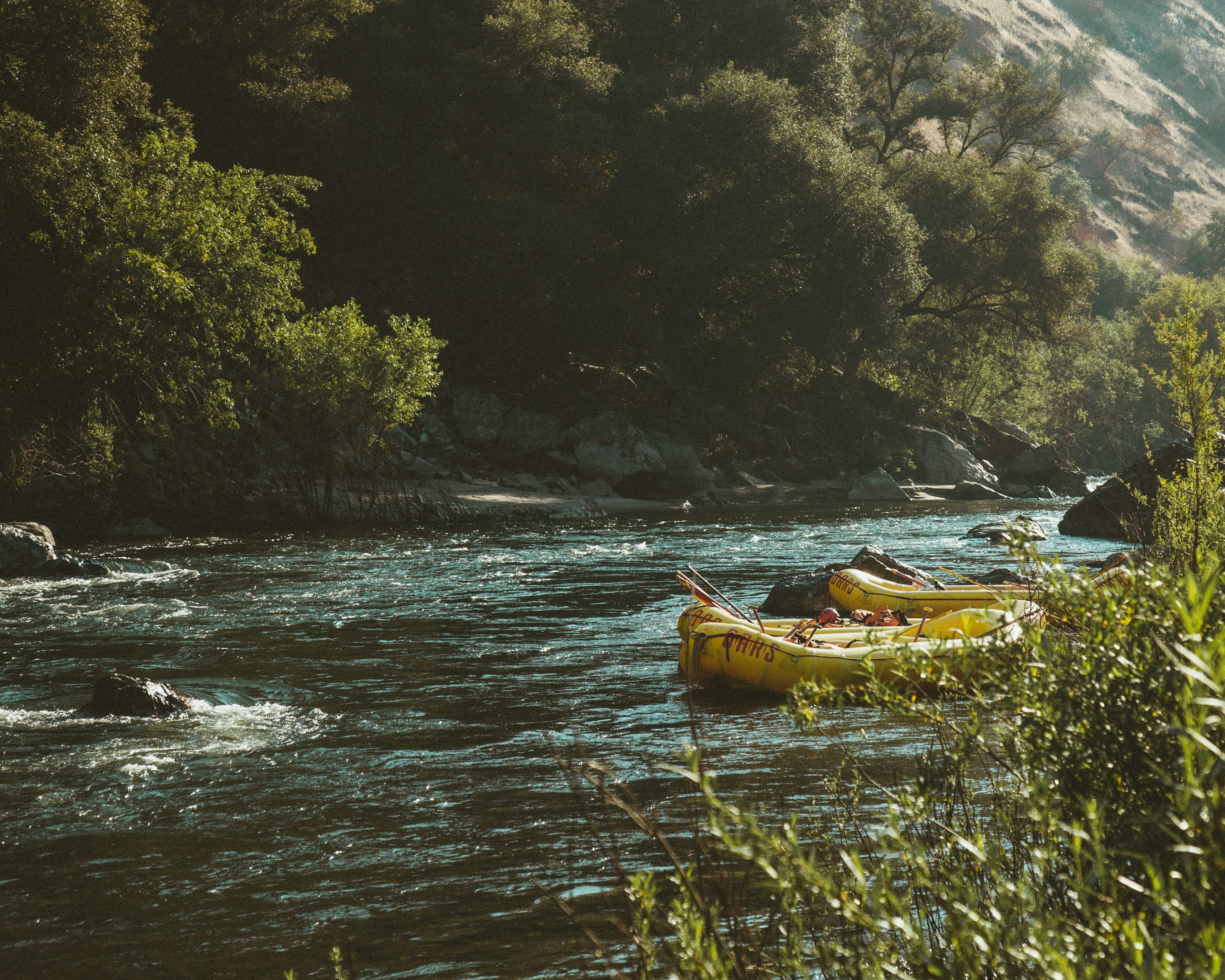 Floating Down The River | two yellow inflatable boats beside river at daytime