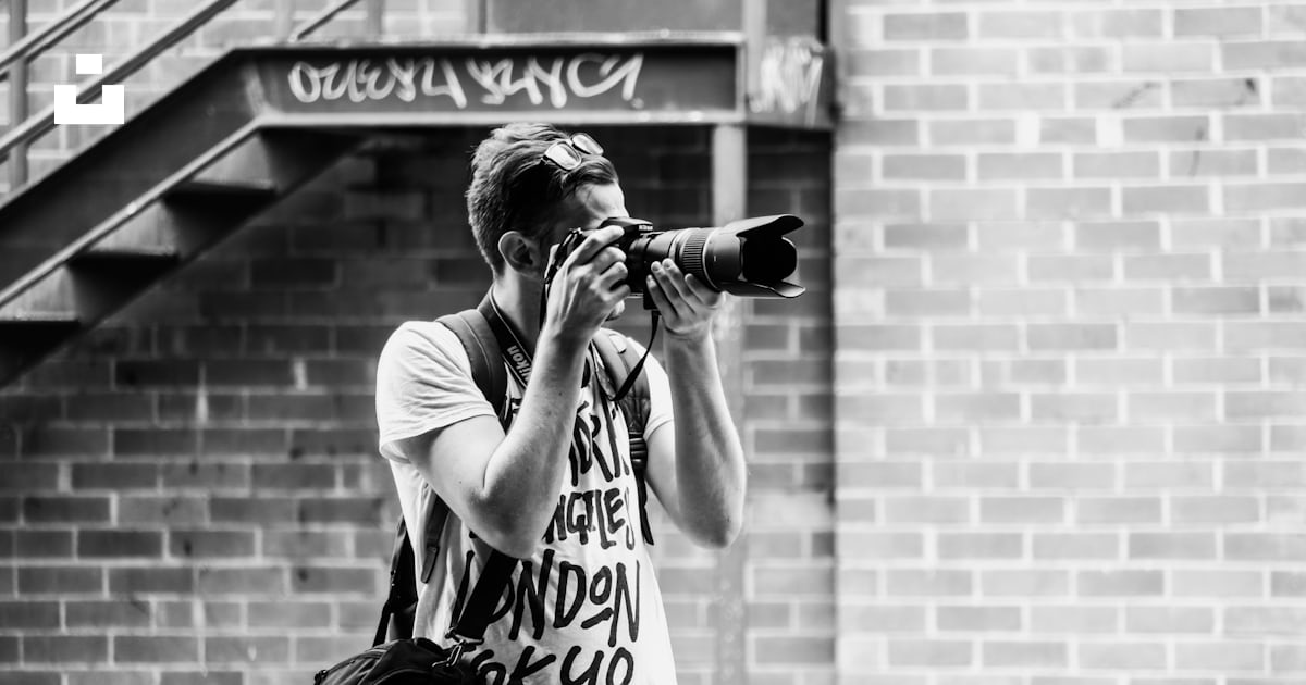 階段の近くに立っているデジタル一眼レフカメラで写真を撮る男の写真 Unsplashのカメラの無料画像