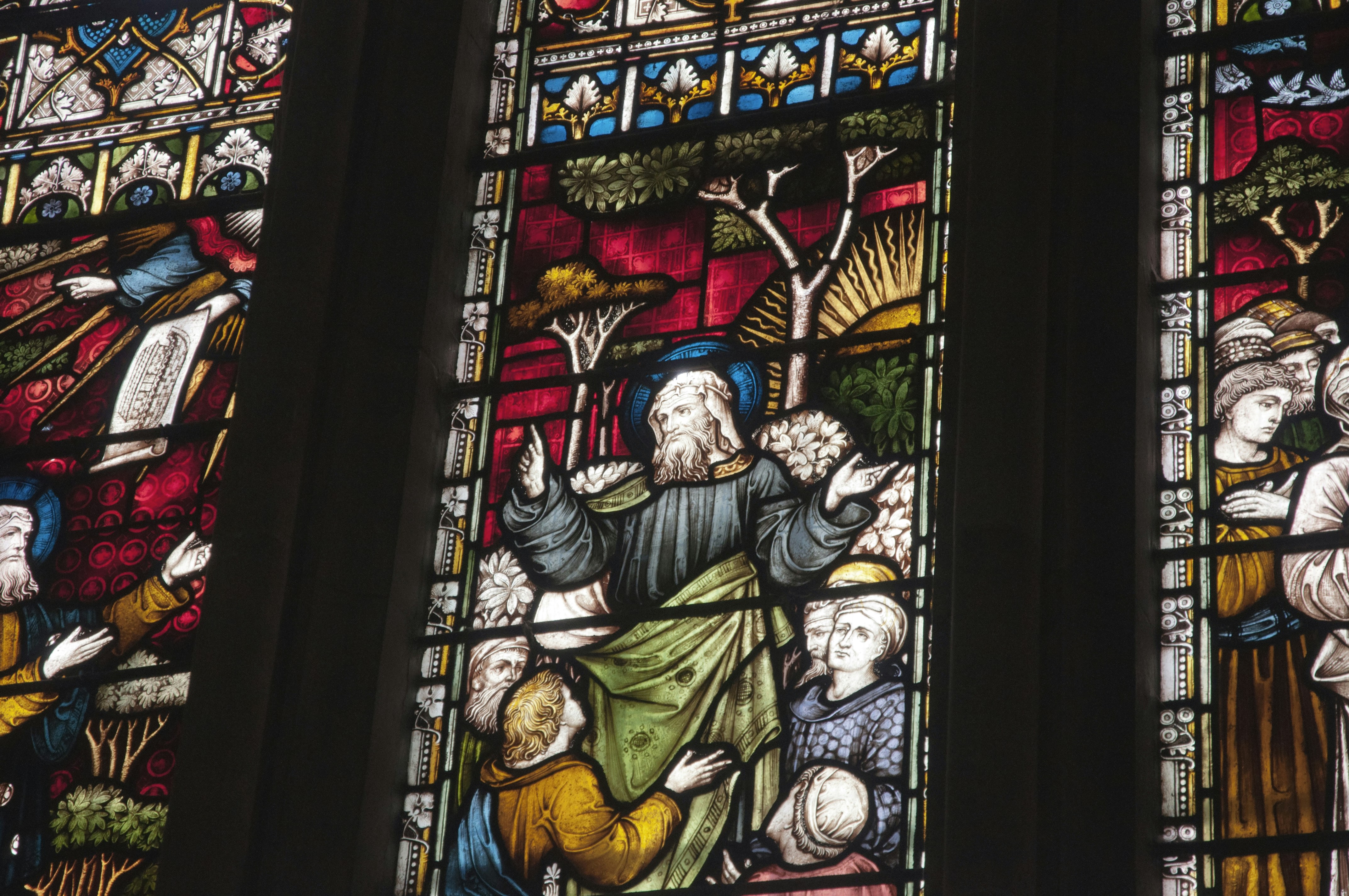 Stained glass window depicting a vibrant biblical scene with figures in rich colors.