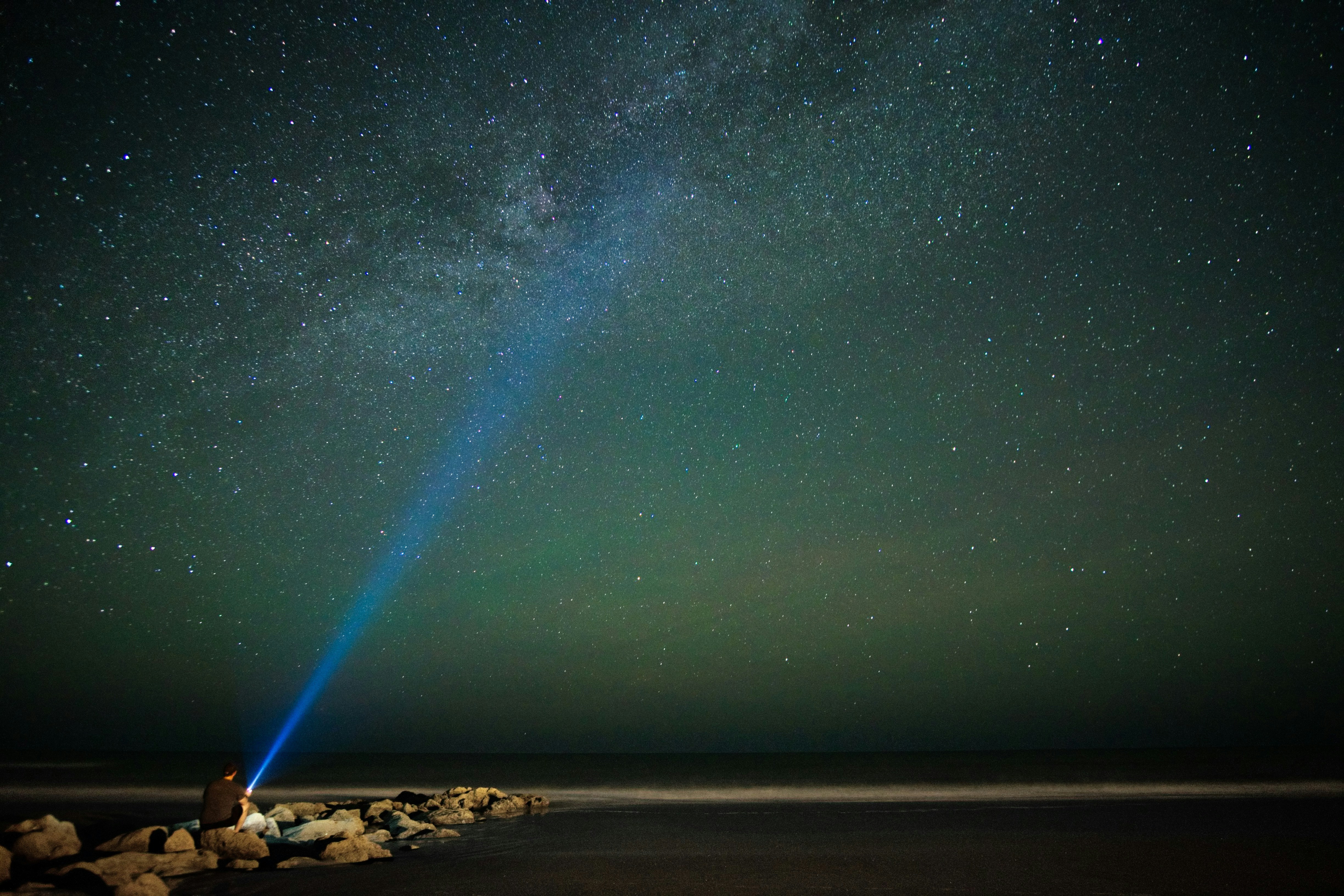 Blue Beacon over the Milky Way: Night on a Rocky Jetty