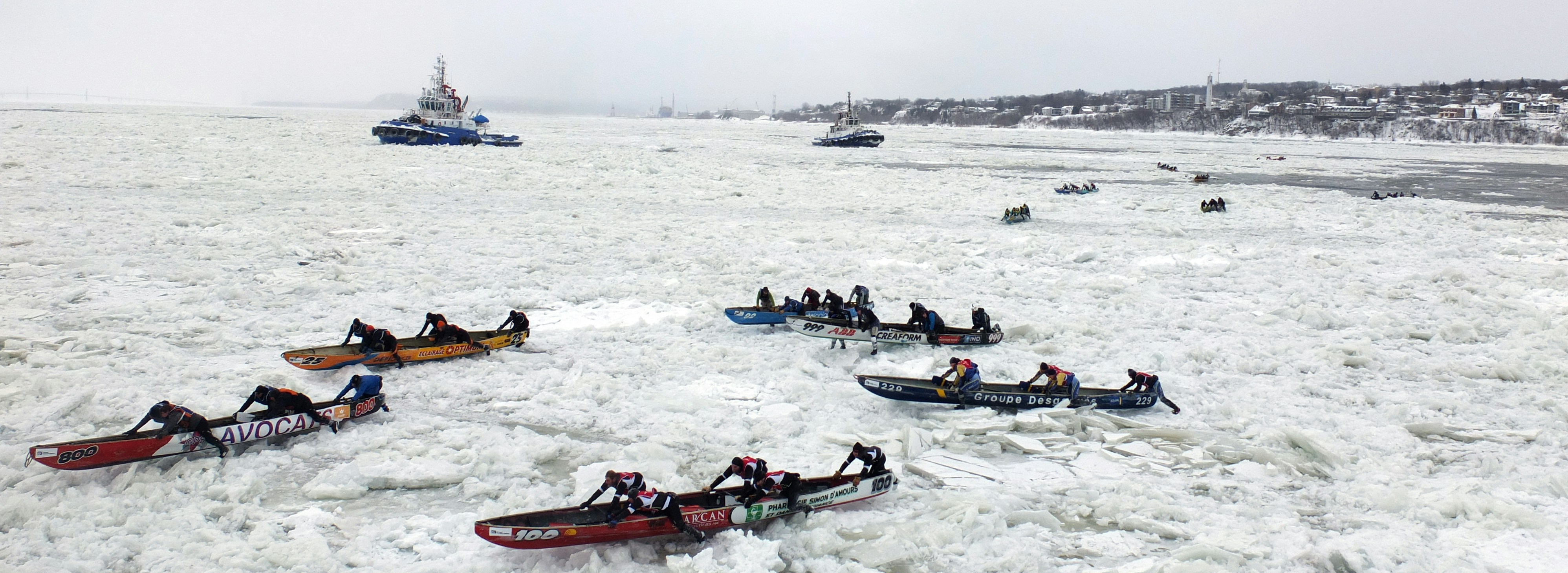 Red Kayaks Thread Through a Frigid Ice Field Under a Pale, Overcast Sky