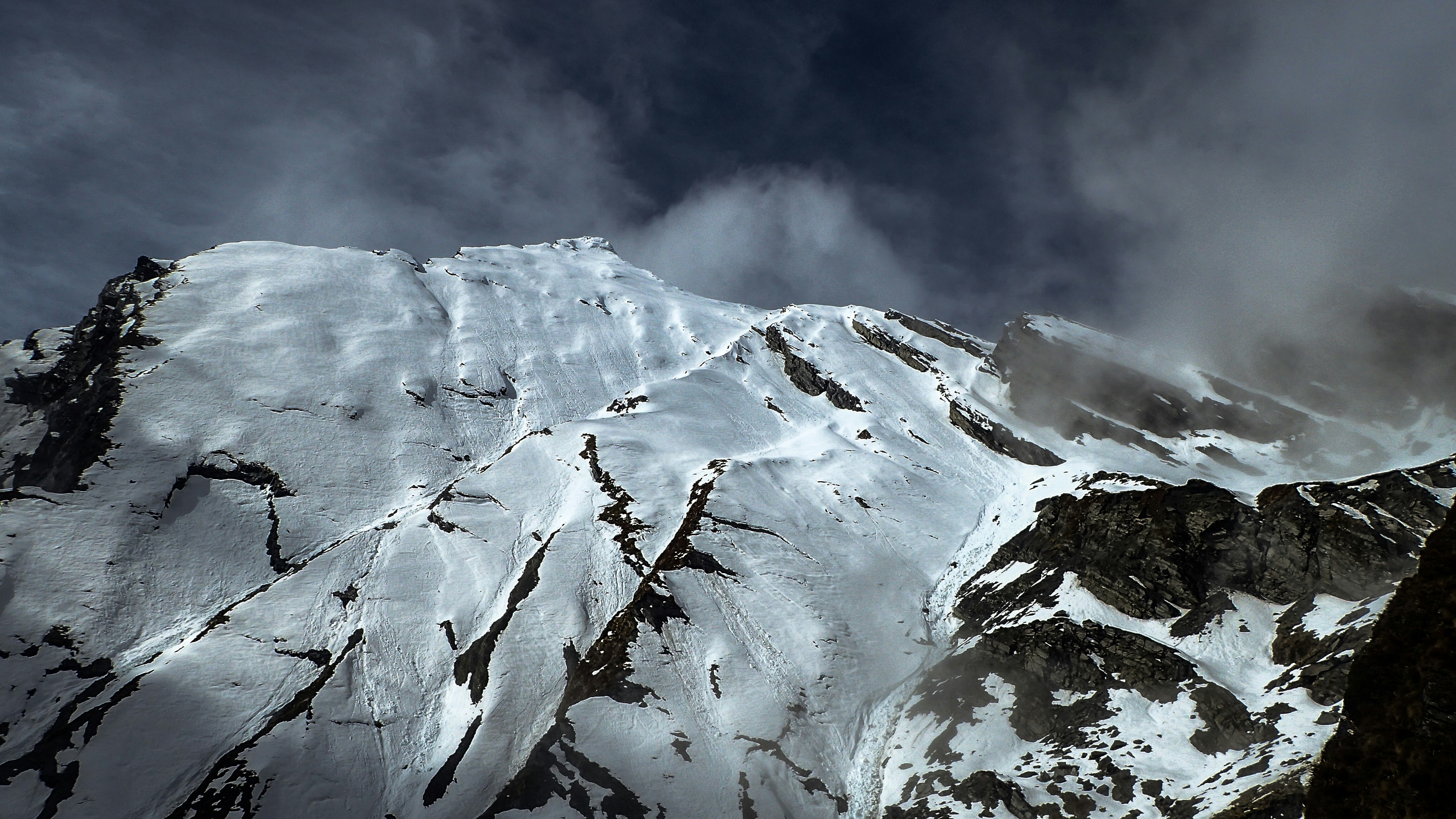 Majestic snow-covered mountain range under a dramatic sky, showcasing the rugged beauty of nature's icy formations.