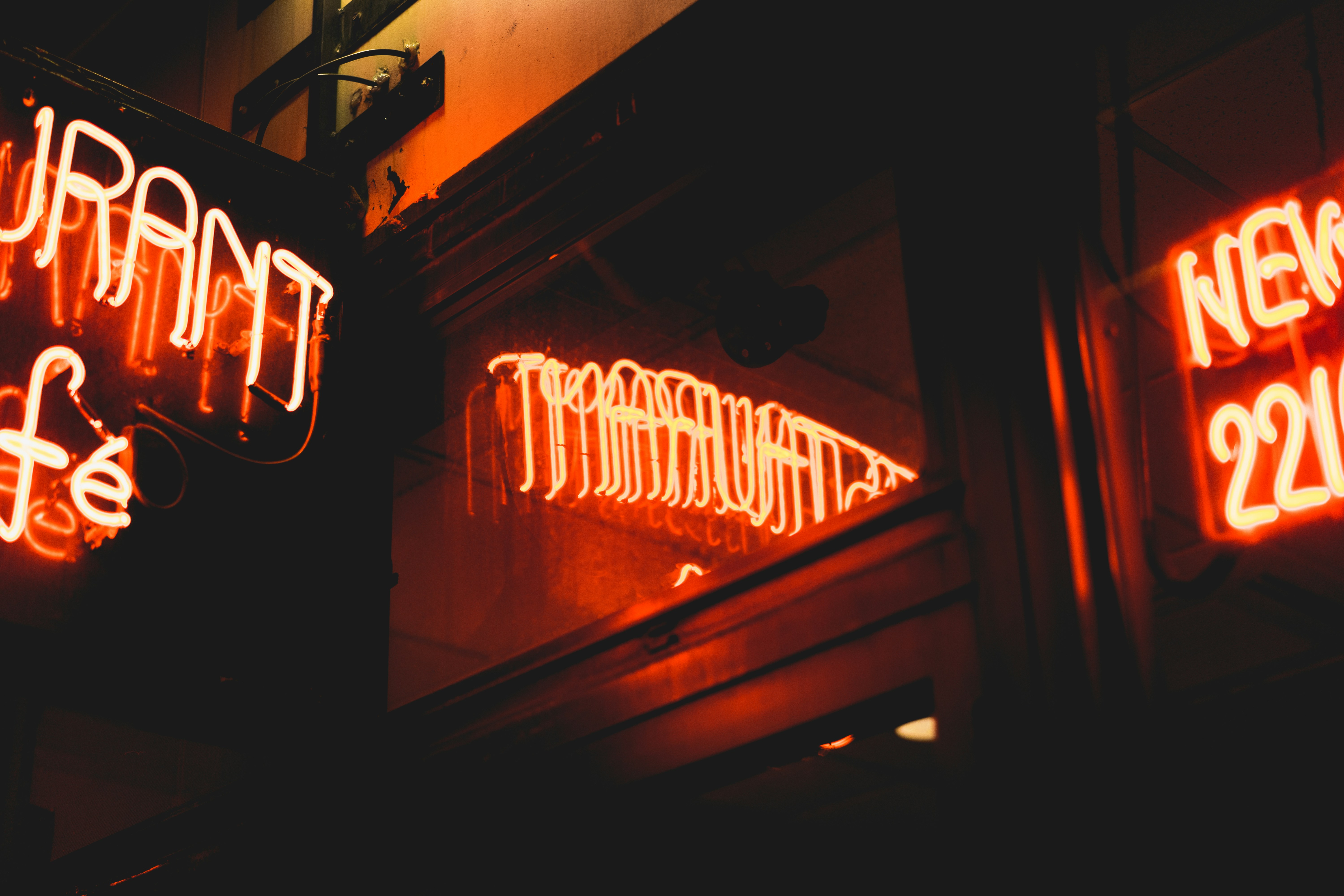 Glowing neon signs reflecting in a window, showcasing the vibrant atmosphere of a city at night. The scene captures the essence of urban dining culture.