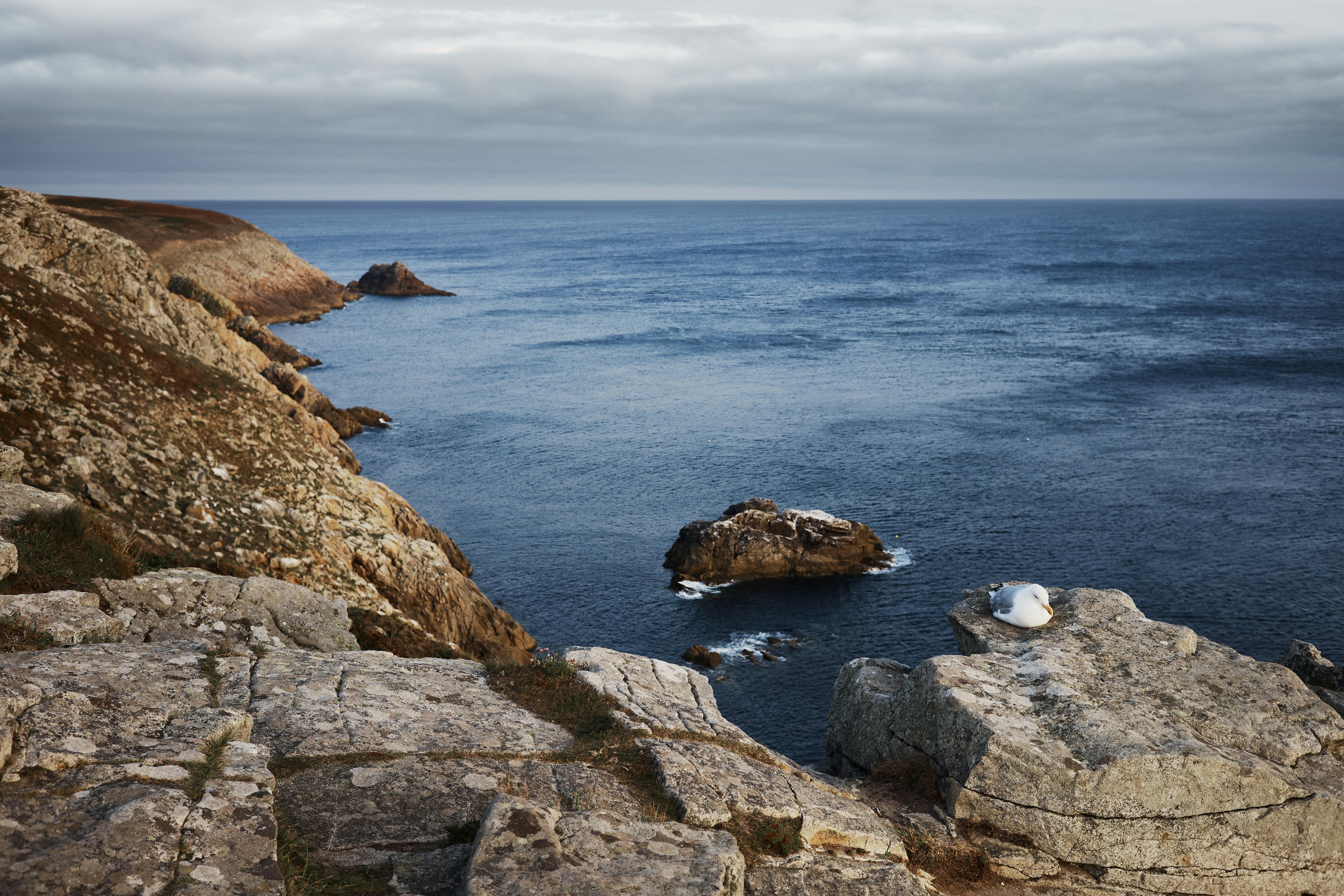 Rock formation island near coastal rocks under nimbus clouds photo ...
