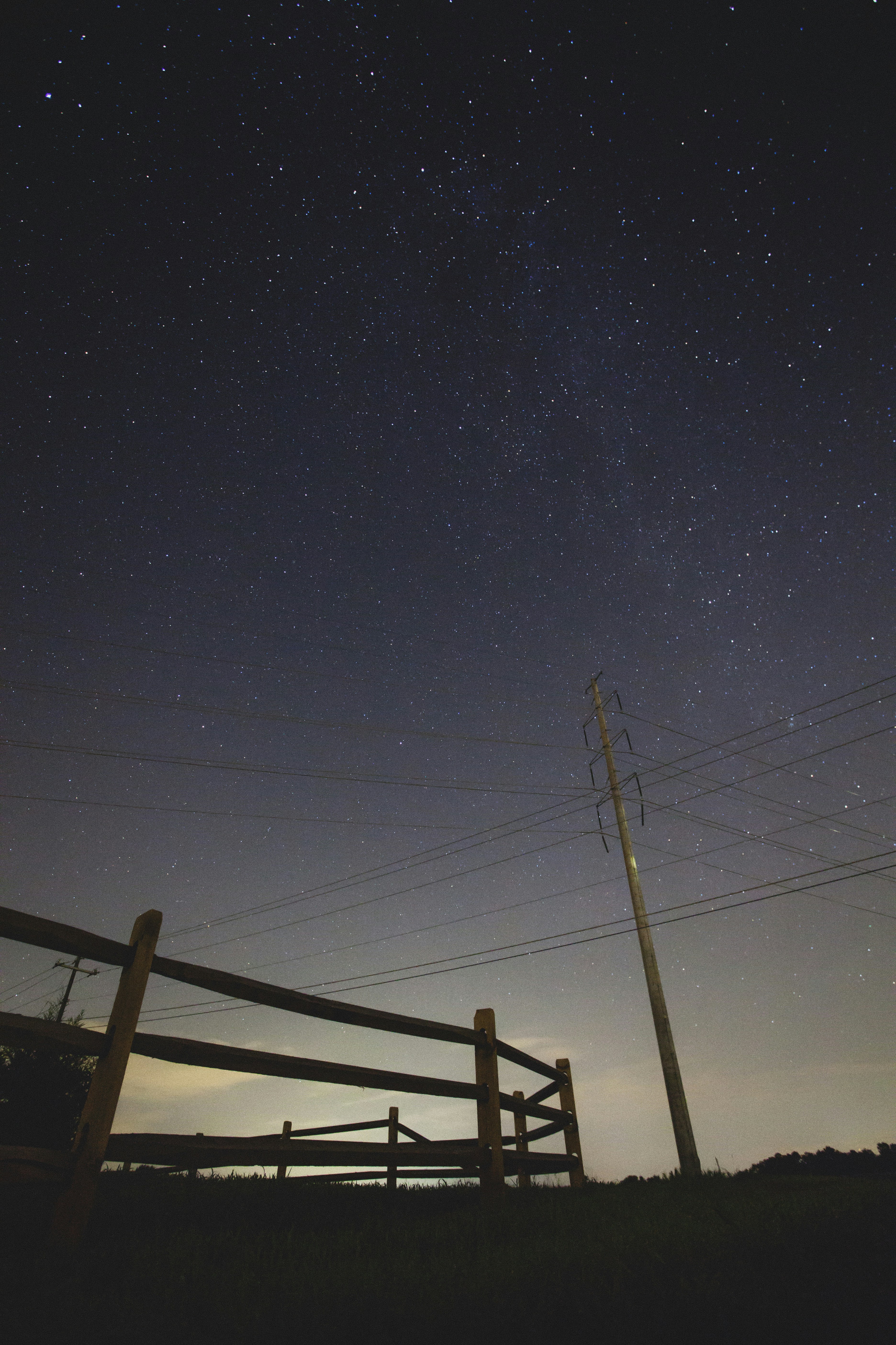 Stars Beyond the Fence: Night Sky Over Quiet Rural Pole