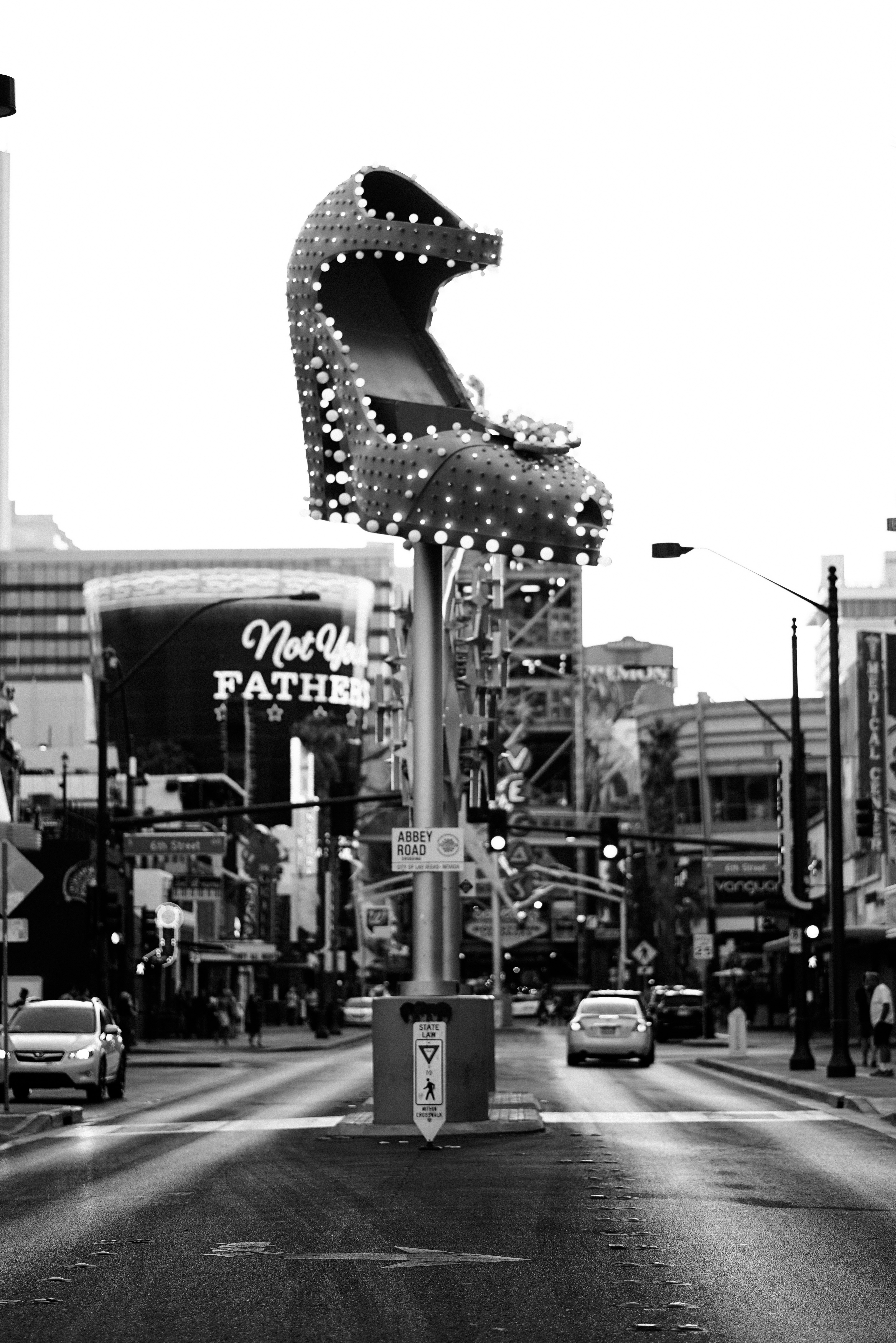 A towering high-heeled shoe sign adorned with lights dominates the street scene, capturing the essence of the vibrant city atmosphere.