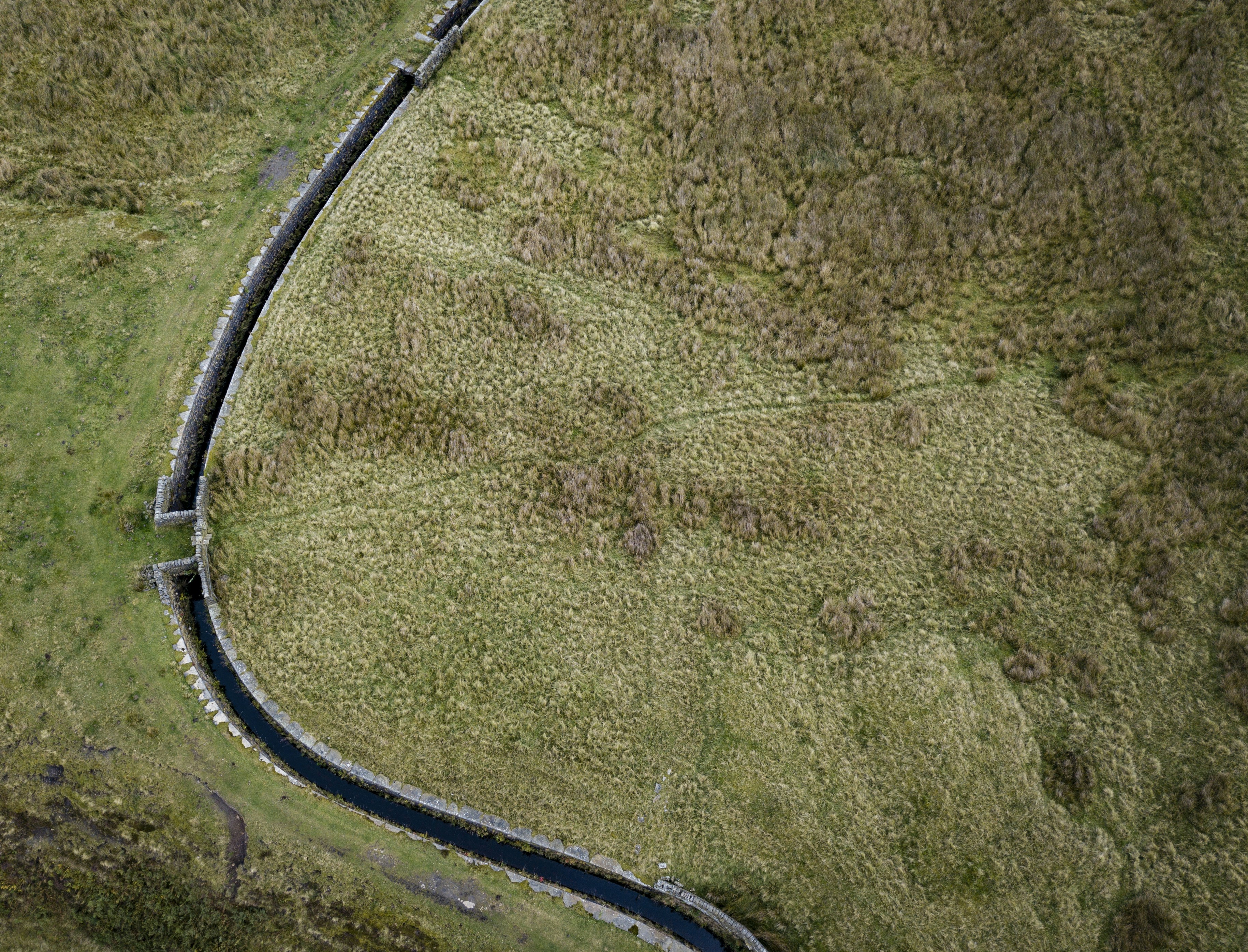 Curving water conduit meanders across Oxenhope moorland, creating distinct lines through the landscape.