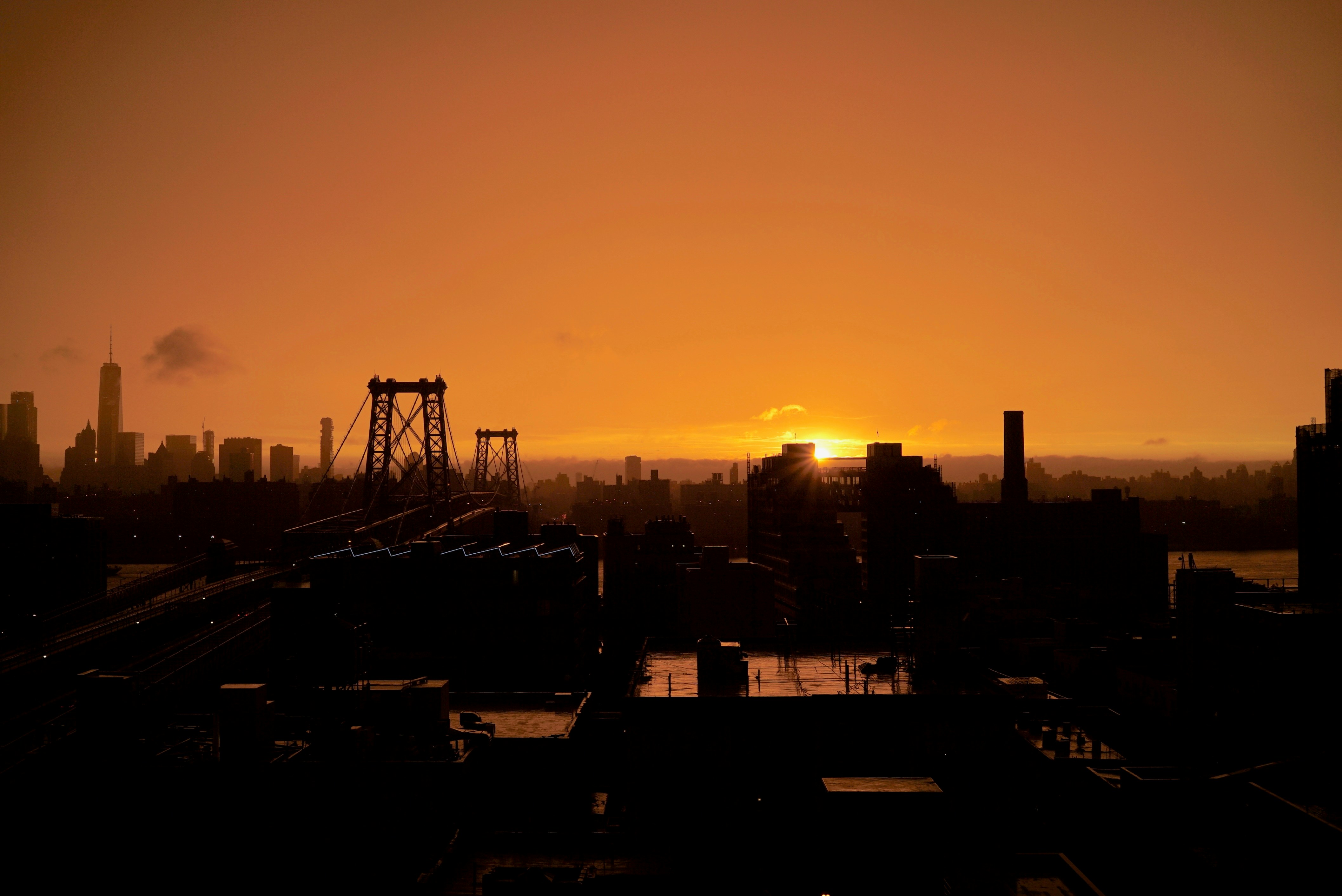 Brooklyn skyline silhouetted against a vibrant orange sunset.