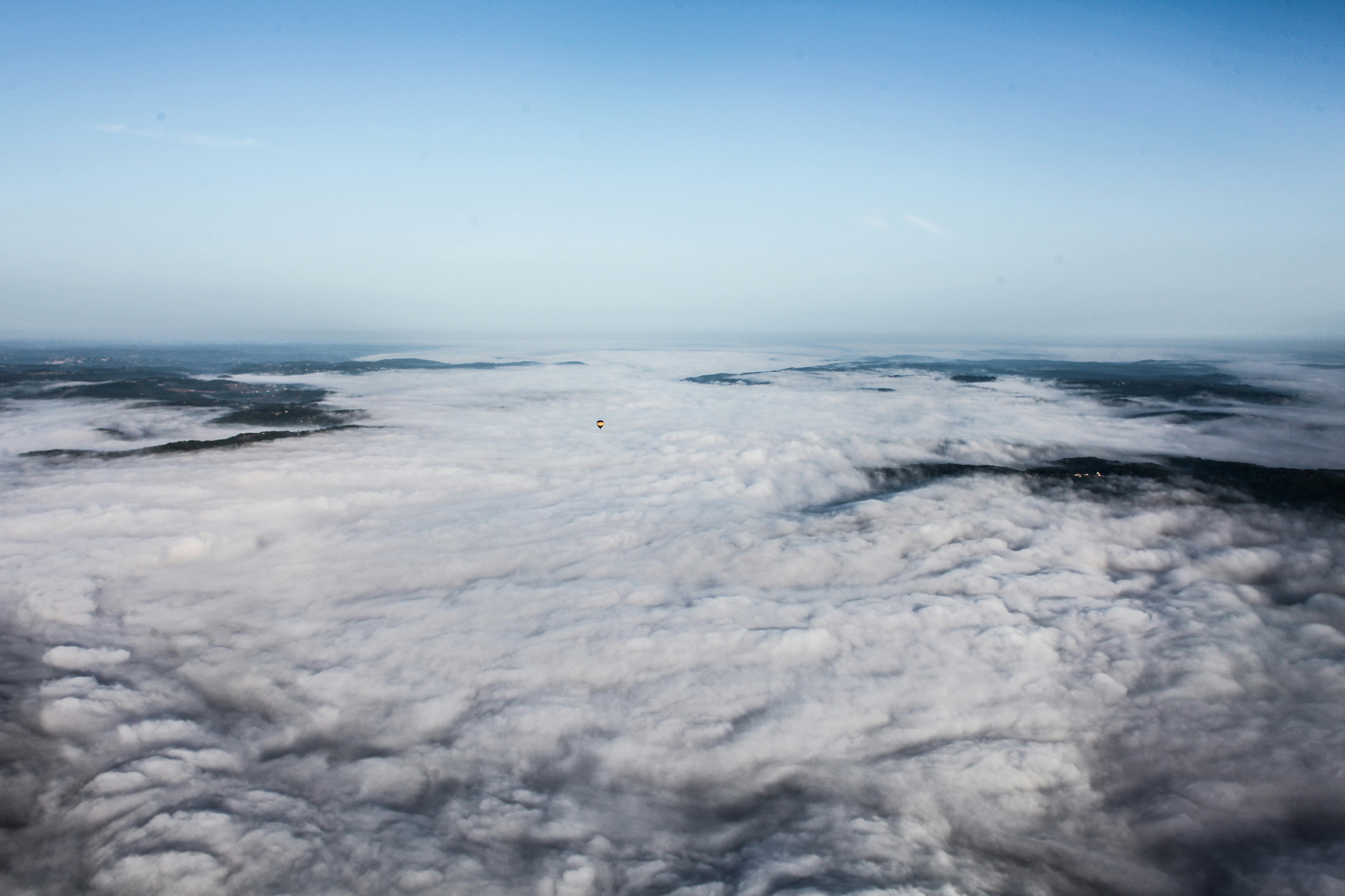 Expansive view of a thick blanket of clouds under a clear blue sky, creating a serene and ethereal atmosphere.
